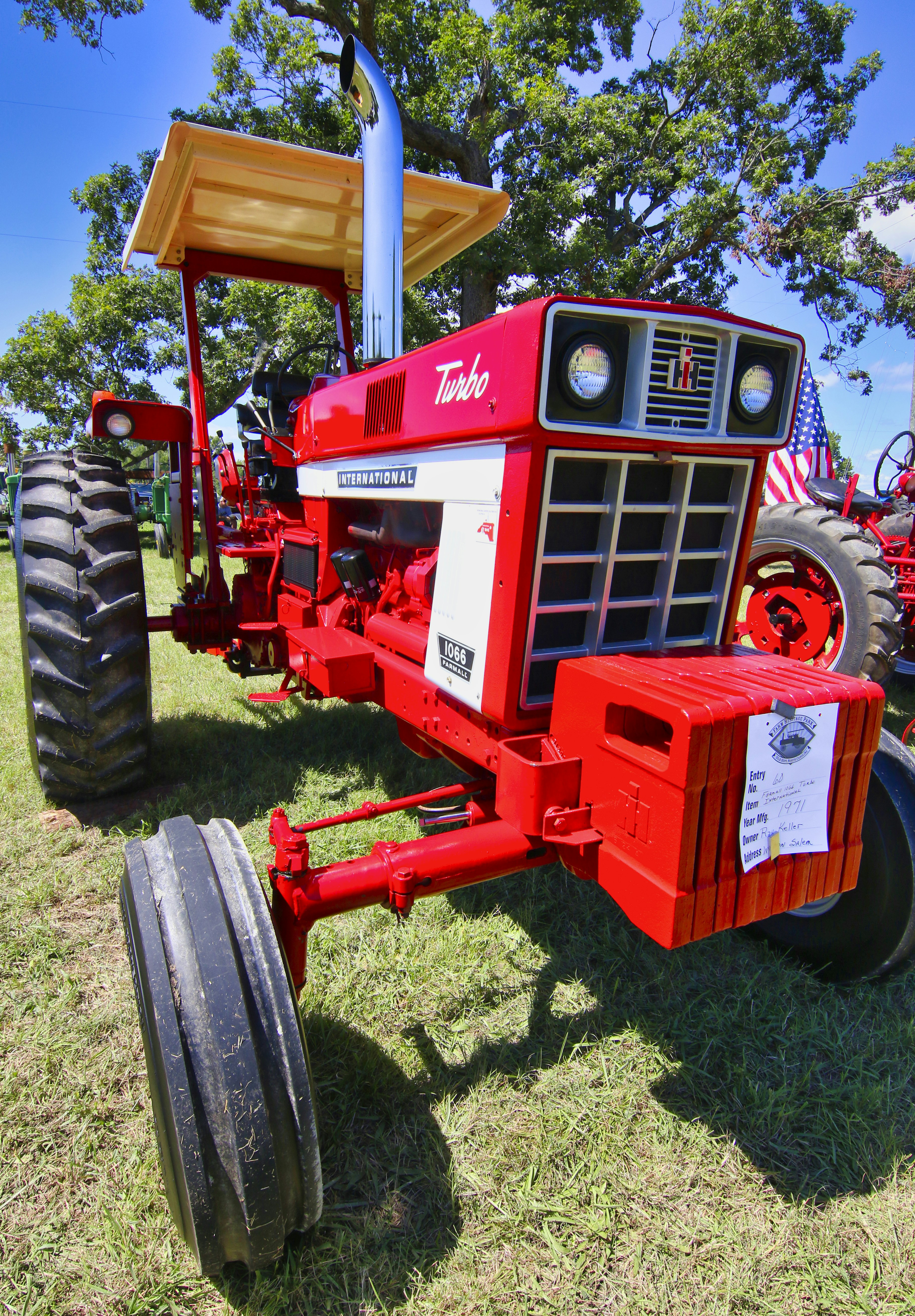 A vibrant International Turbo tractor stands prominently on a grassy field, showcasing its classic design and bright red color. The tractor's details highlight its vintage charm.