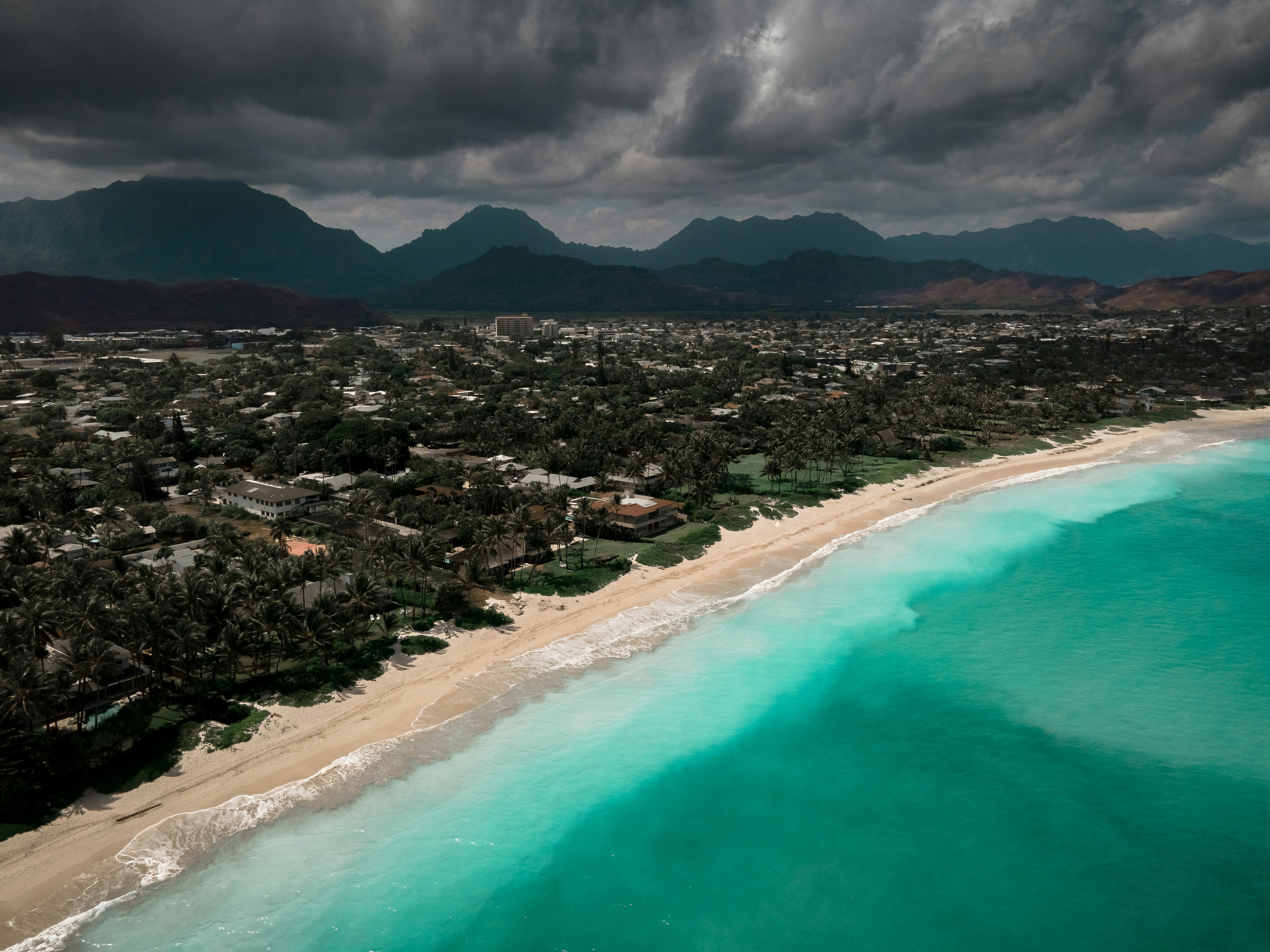 Turquoise Coastline Under Storm Skies: Aerial Panorama of Beach and Town