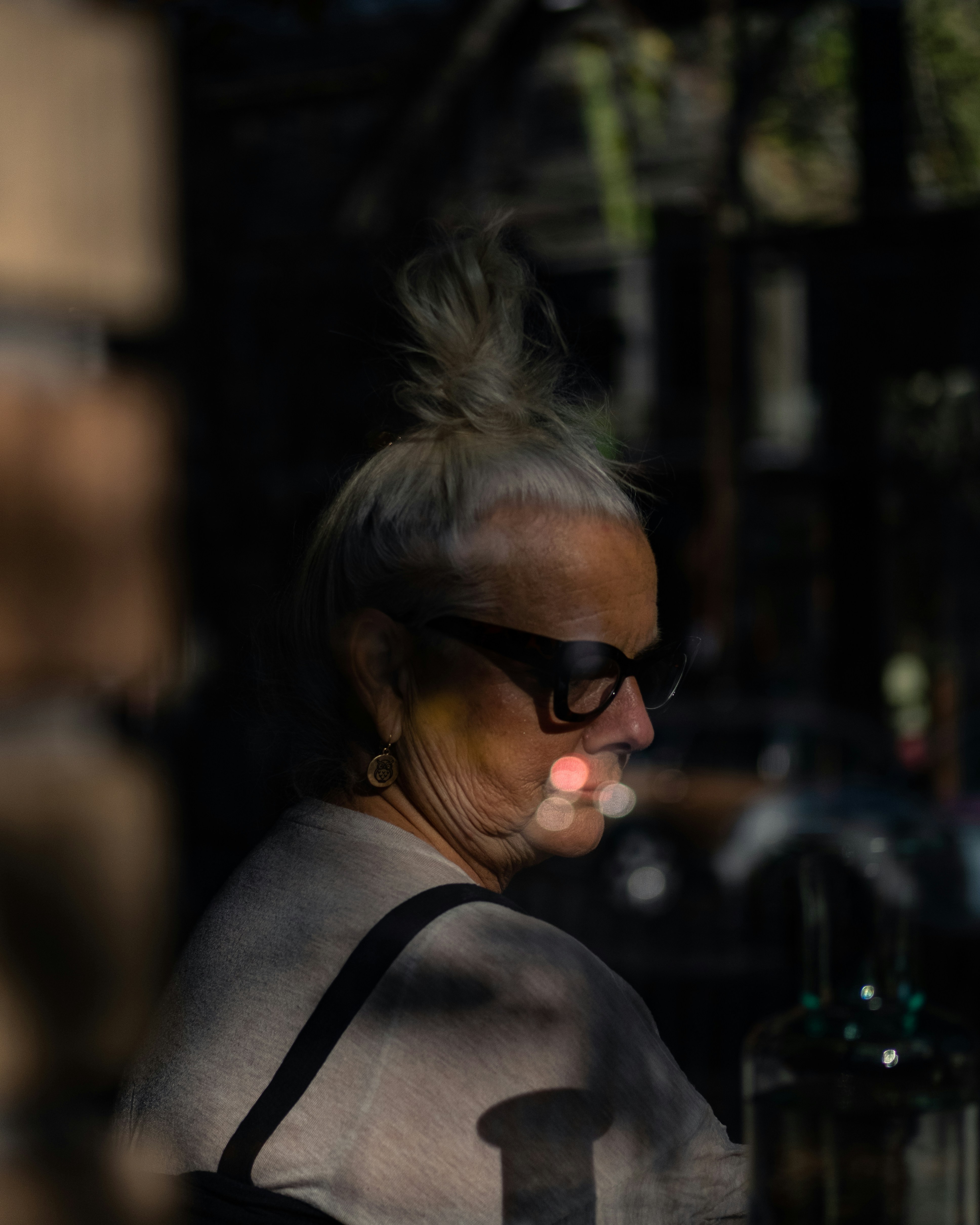 Shadowed Profile: A Moody Street-Cafe Portrait with a Glint of Light