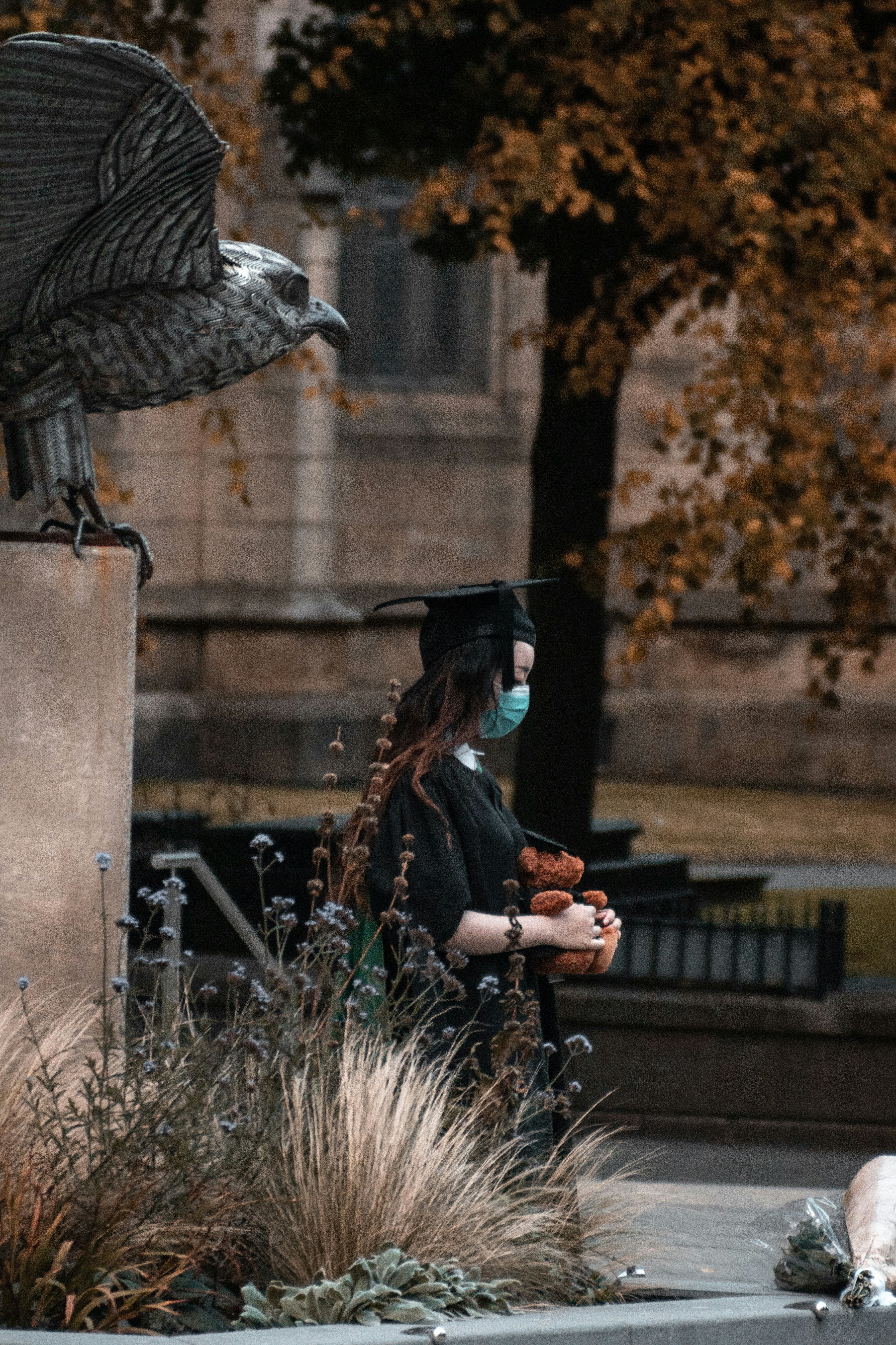 Masked Graduate by the Eagle: An Autumn Campus Portrait