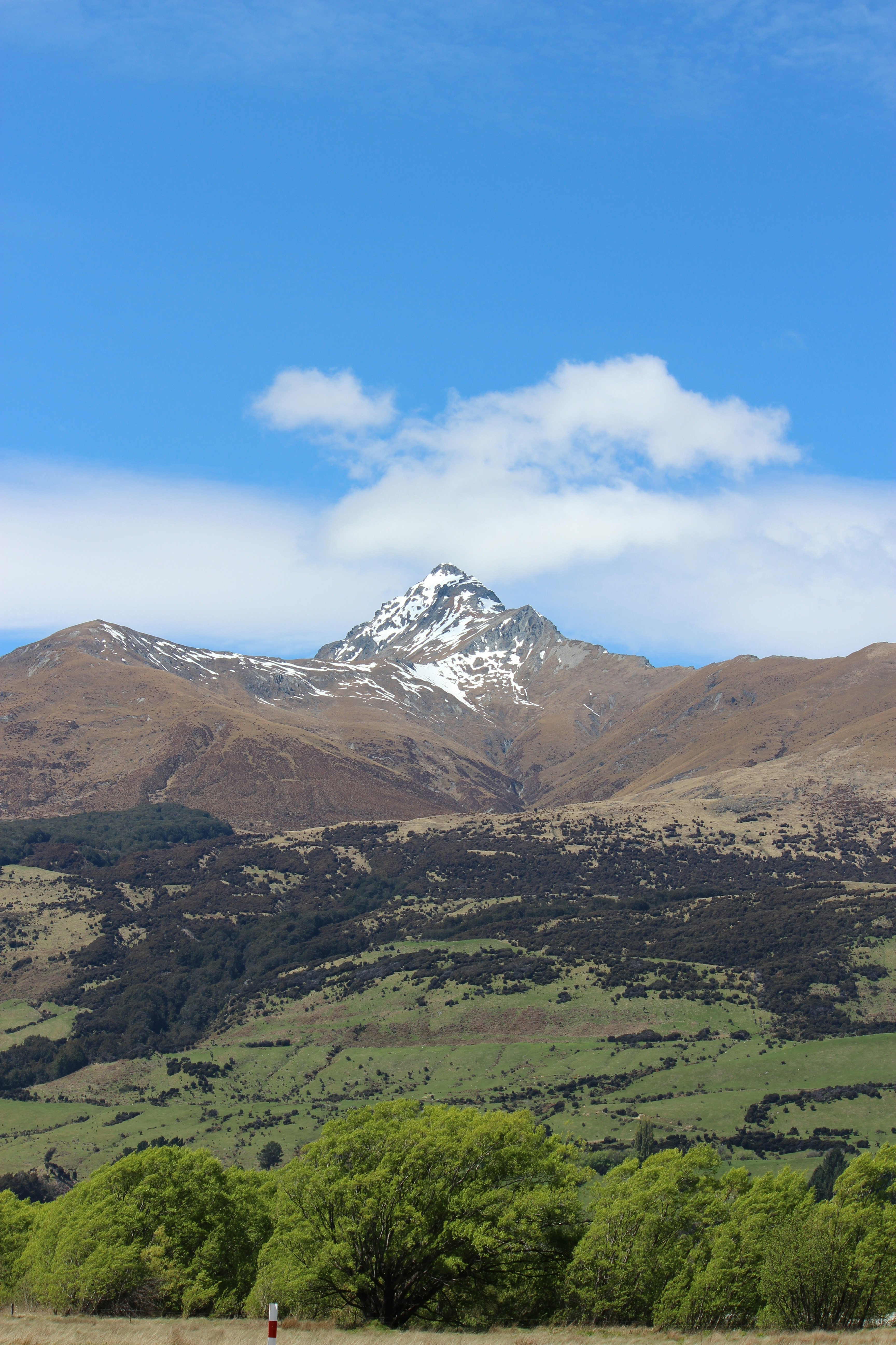 Snow-Capped Summit Framed by Green Valleys Under a Bright Blue Sky