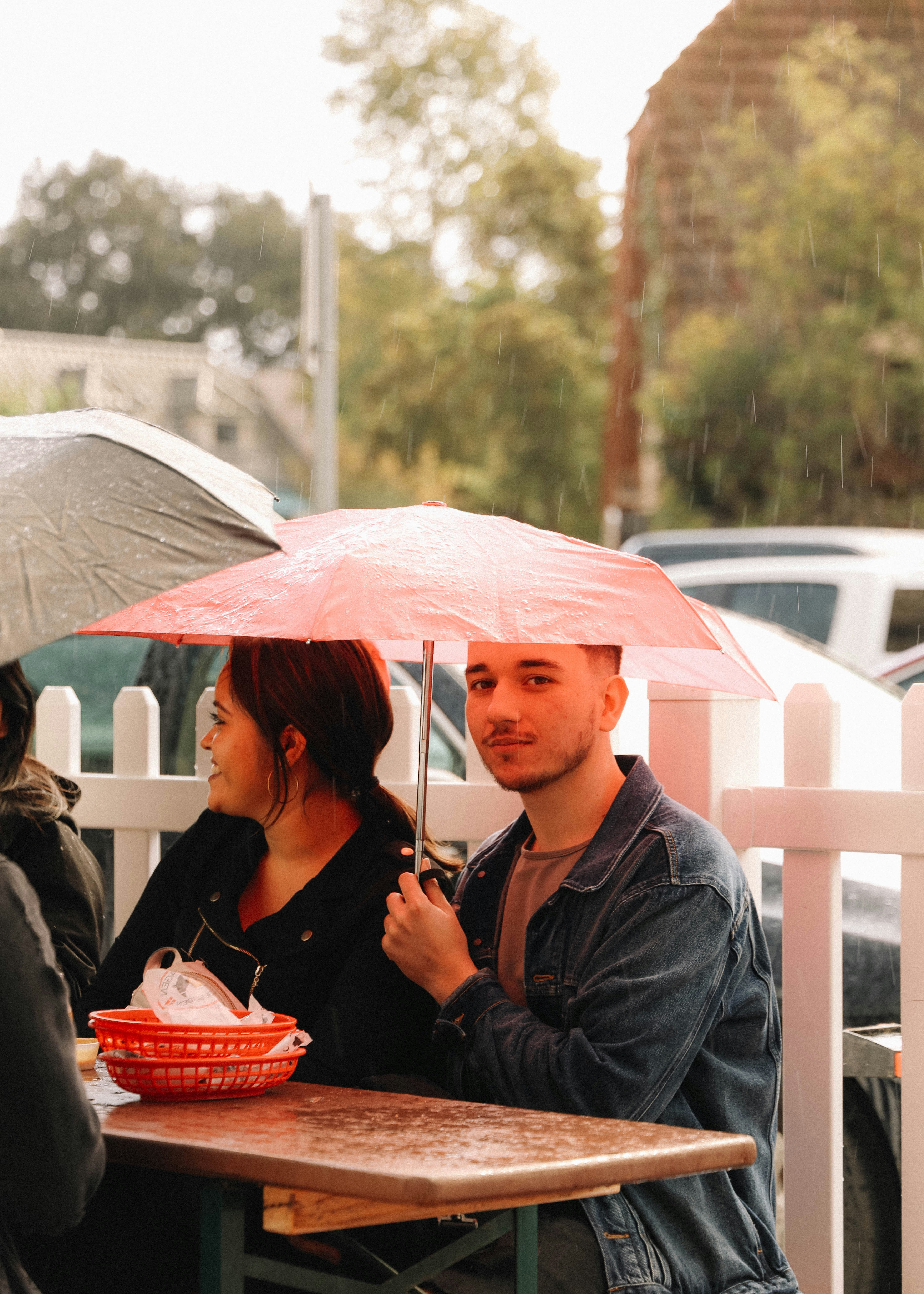 Under a Pink Umbrella, Quiet Connection at an Outdoor Café in the Rain