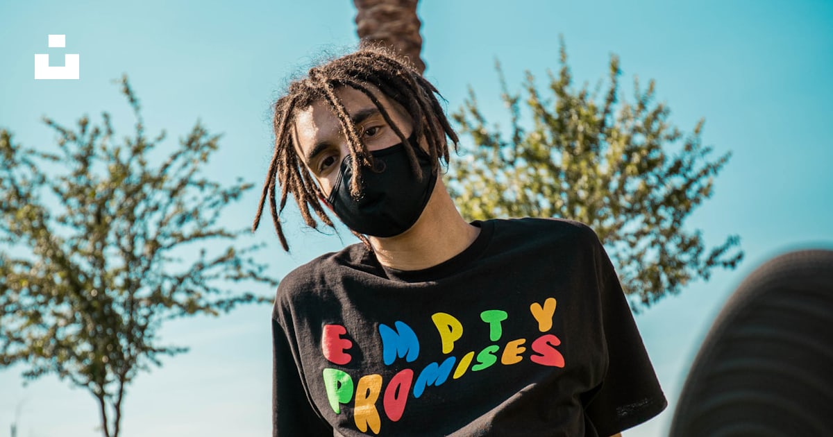 緑の芝生のフィールドに座っている黒いクルーネックのtシャツと黒いズボンの男の写真 Unsplashのファッションの無料画像