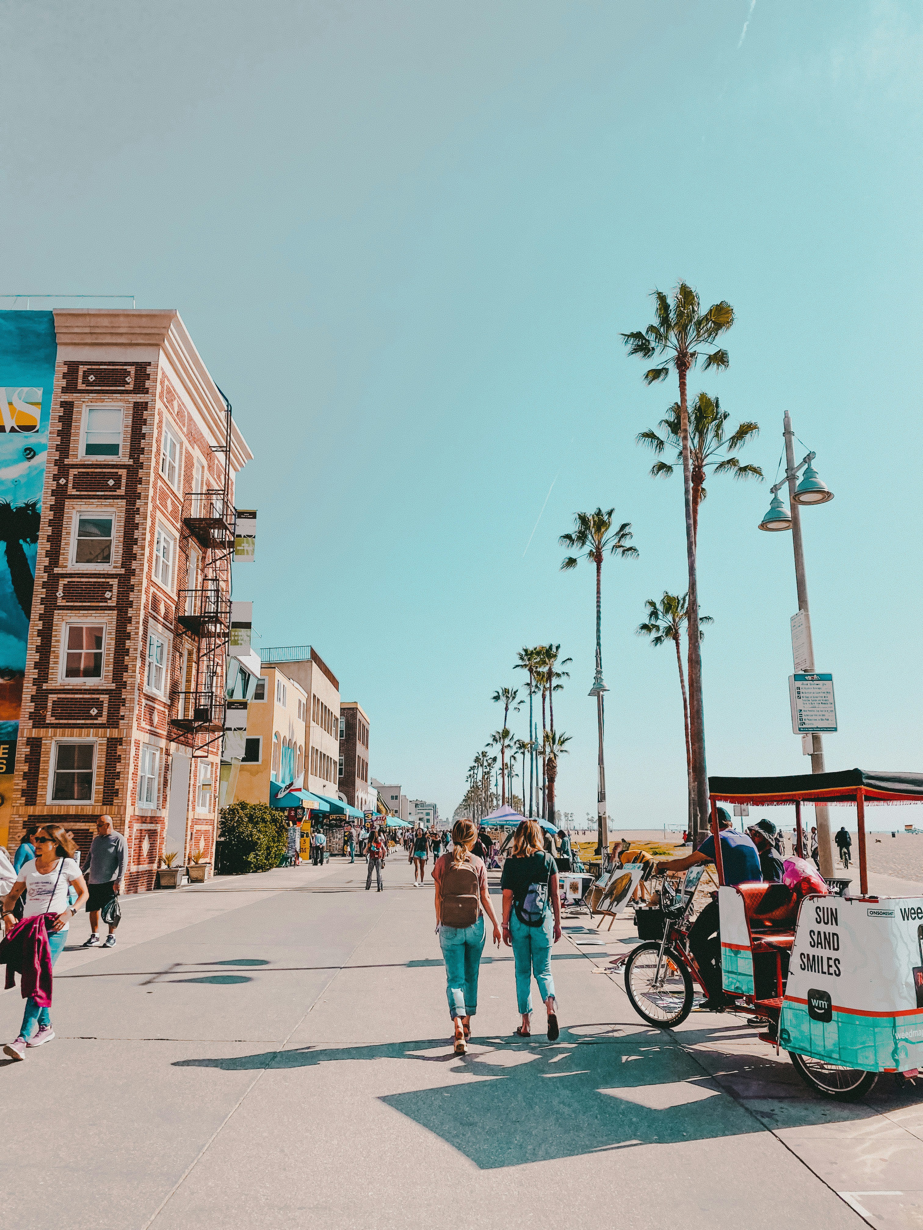 Sunlit Promenade: Palm Trees, Beachfront Path, and People in Motion