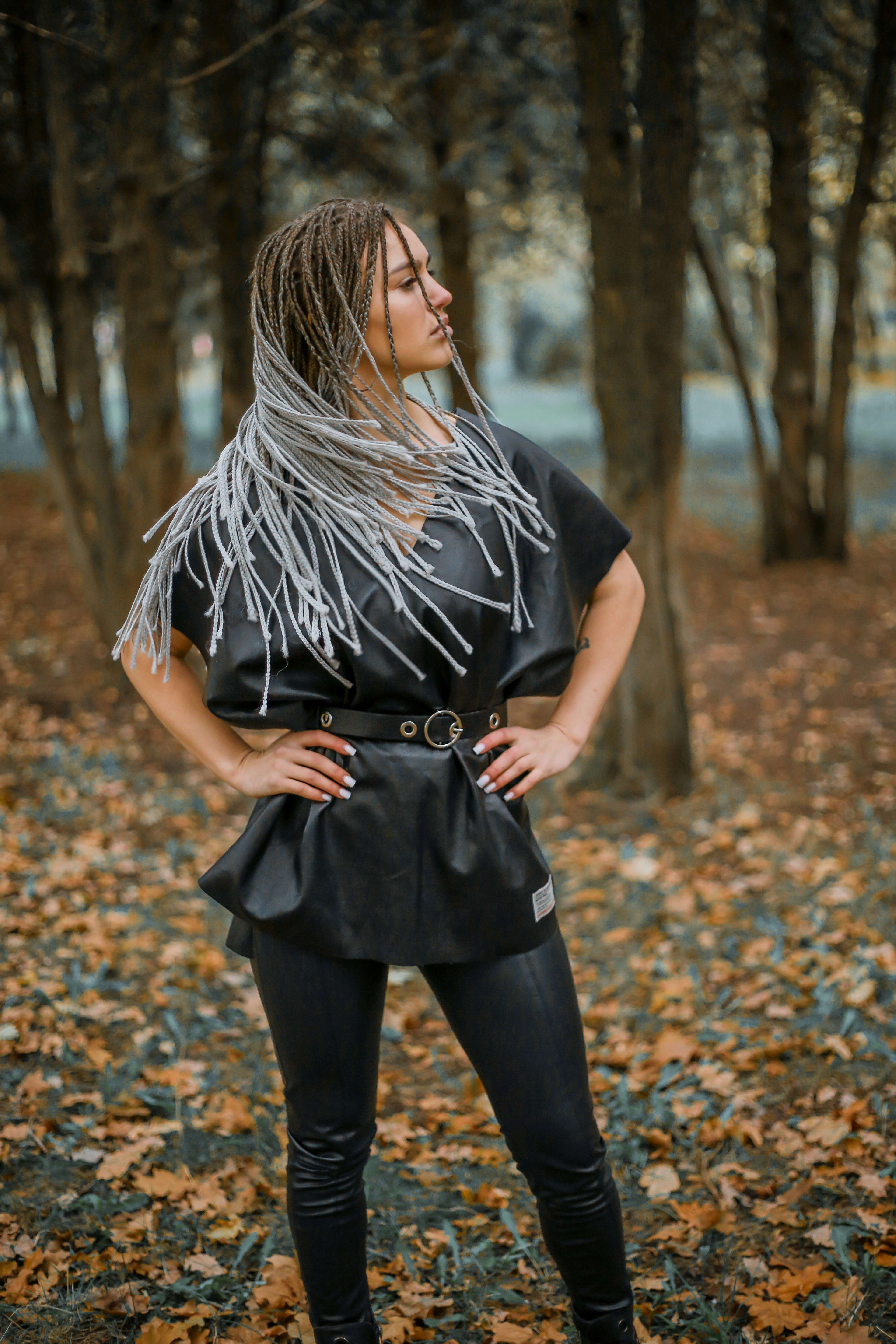 woman in black dress standing on dried leaves during daytime
