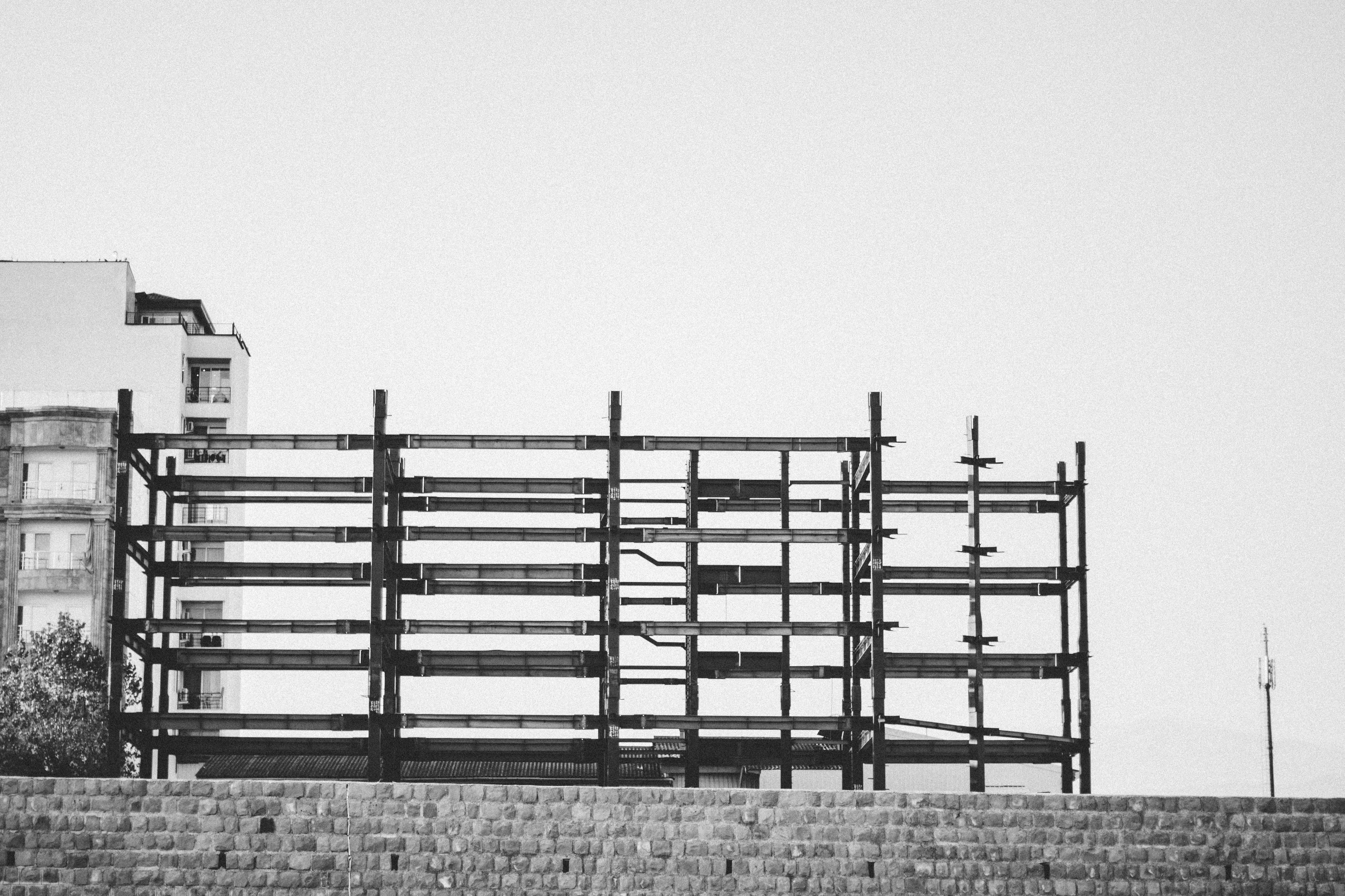 A monochromatic depiction of a skeletal building structure against a clear sky, emphasizing architectural lines and urban development.