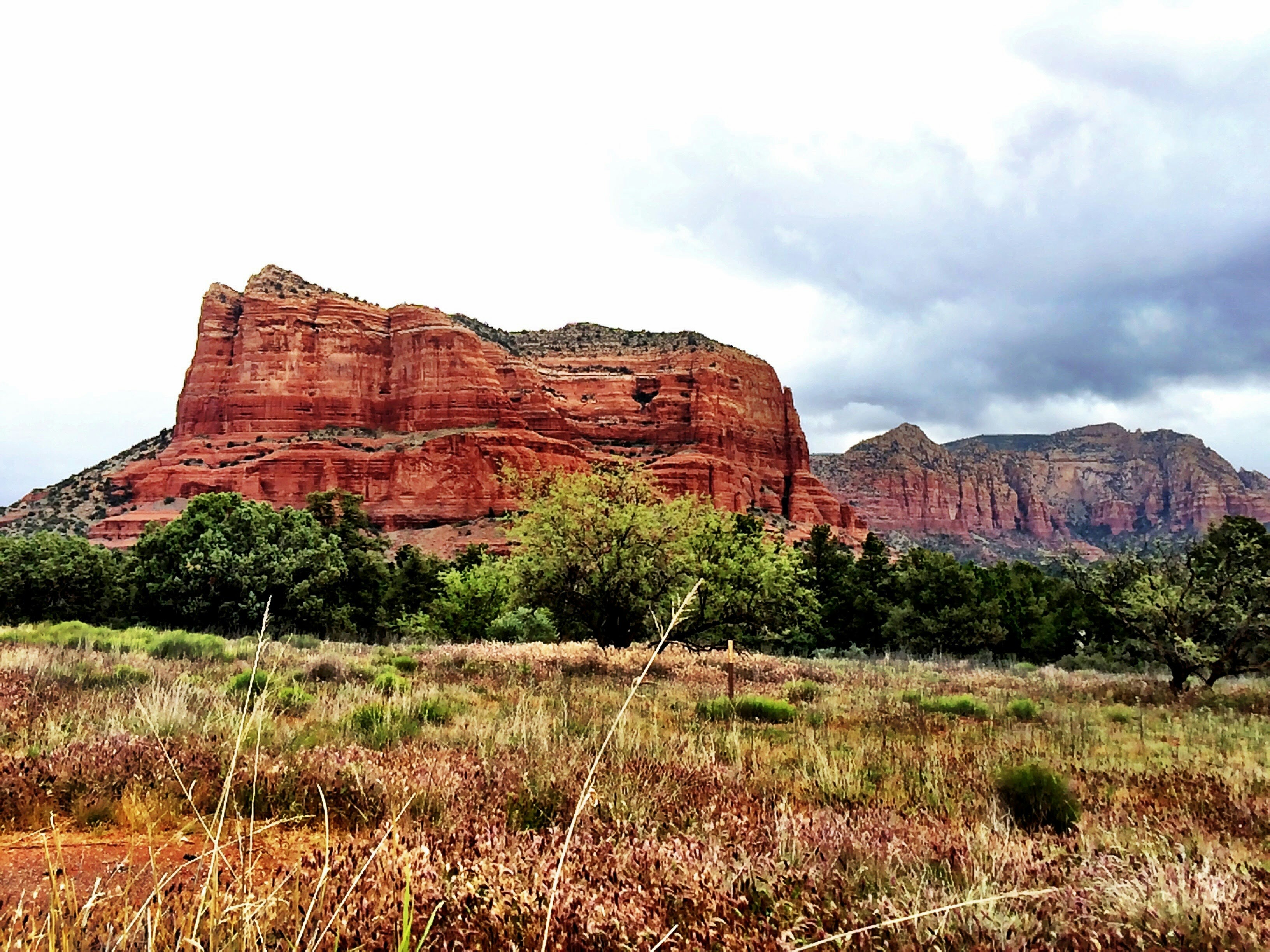 Red Limestone Citadel Framed by Prairie Grasses Under Clouded Skies