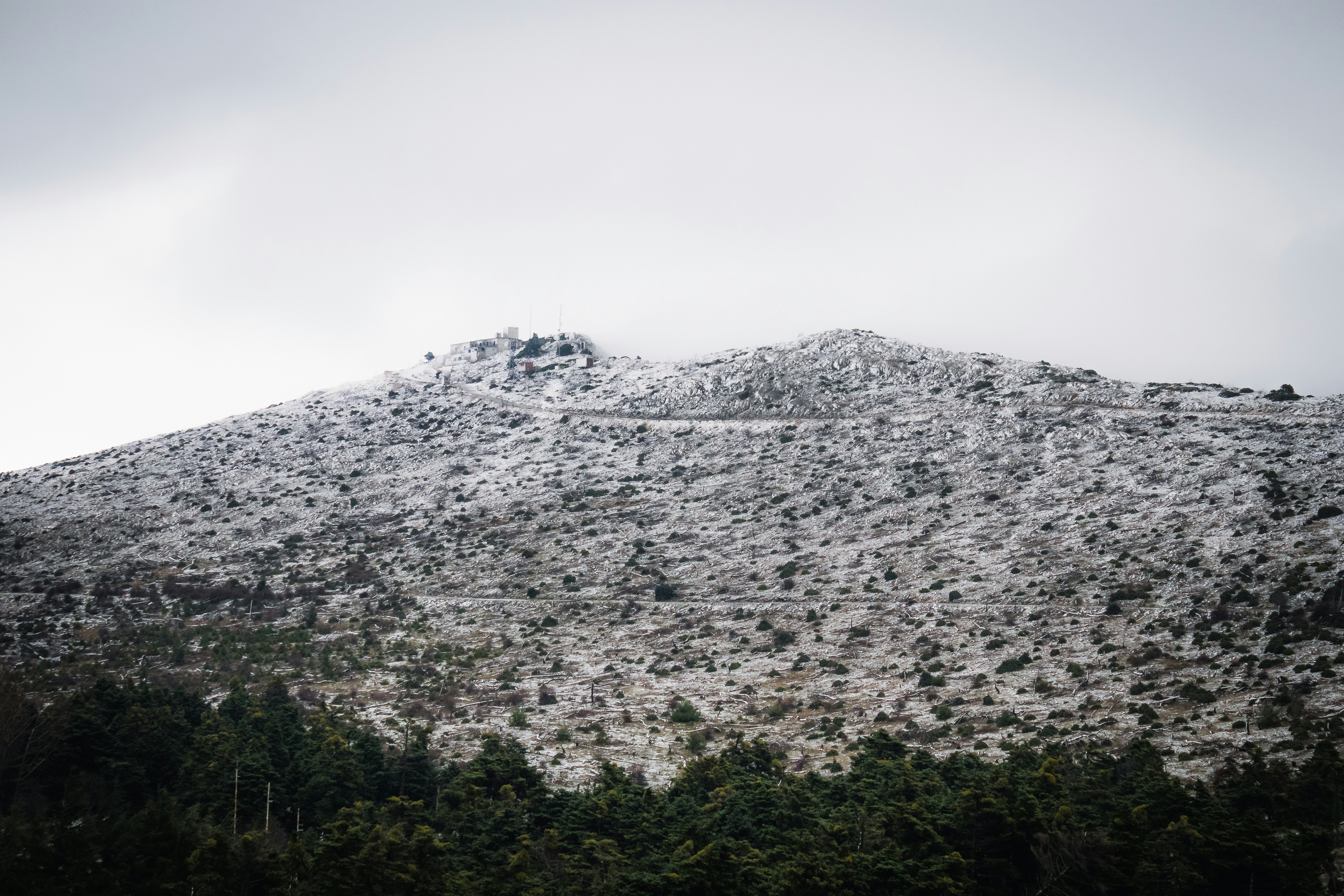 Snow-Dusted Ridge Crowned by Granite Beneath a Cloudy Sky