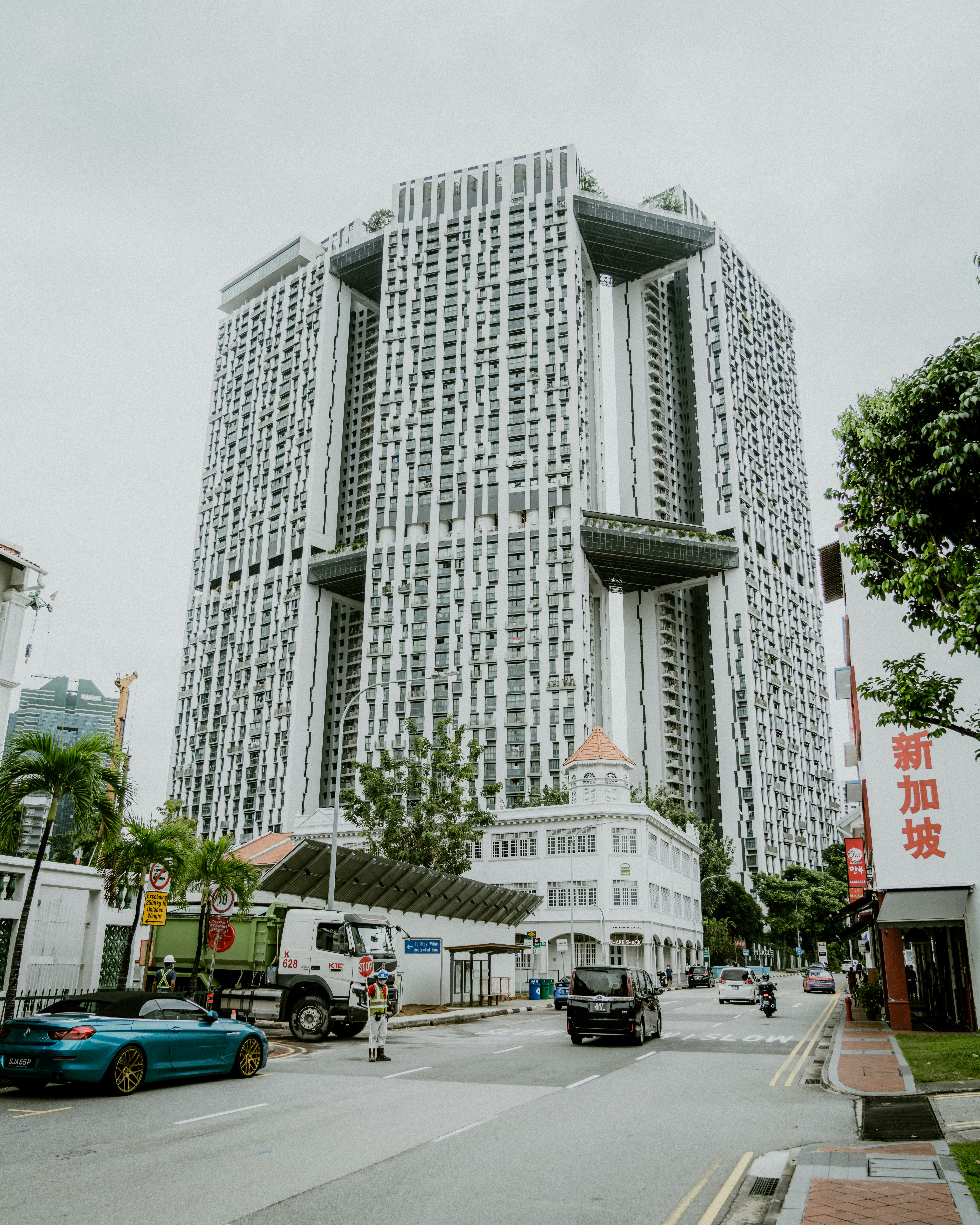 Perforated Monolith Looms Over a Lively City Street
