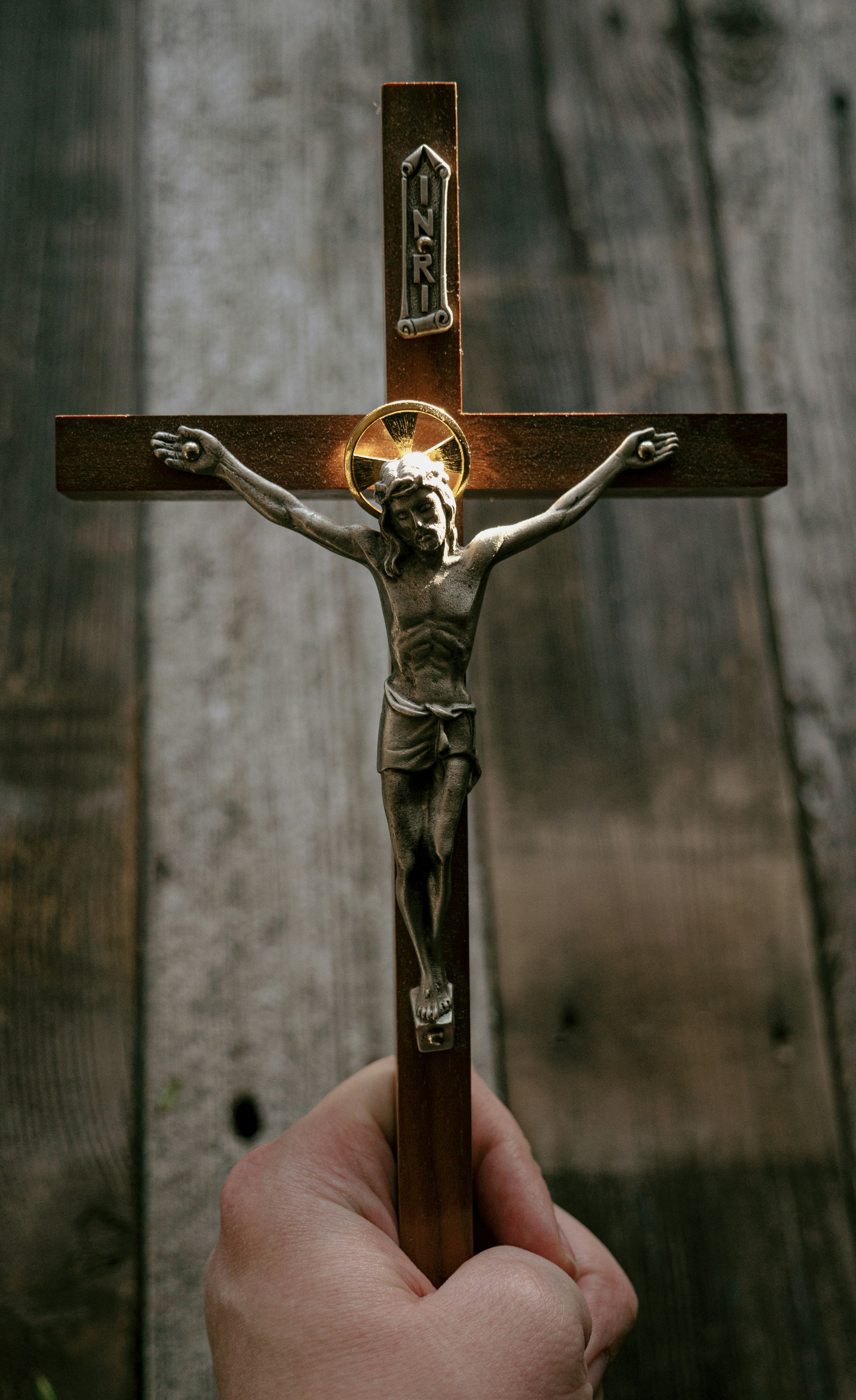 gold crucifix on brown wooden fence