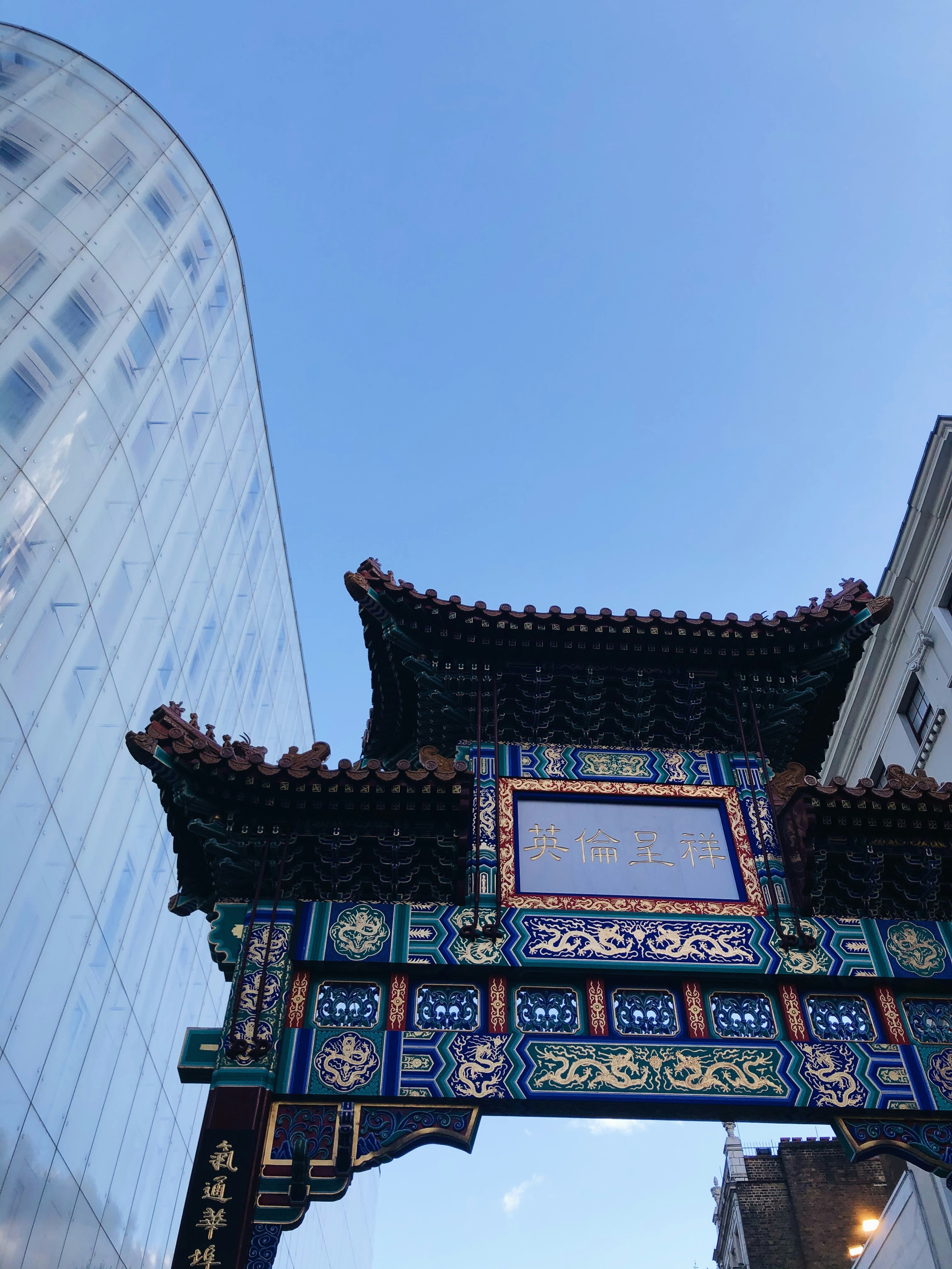 Intricate Chinese archway stands proudly against a backdrop of contemporary architecture, showcasing a blend of tradition and modernity.