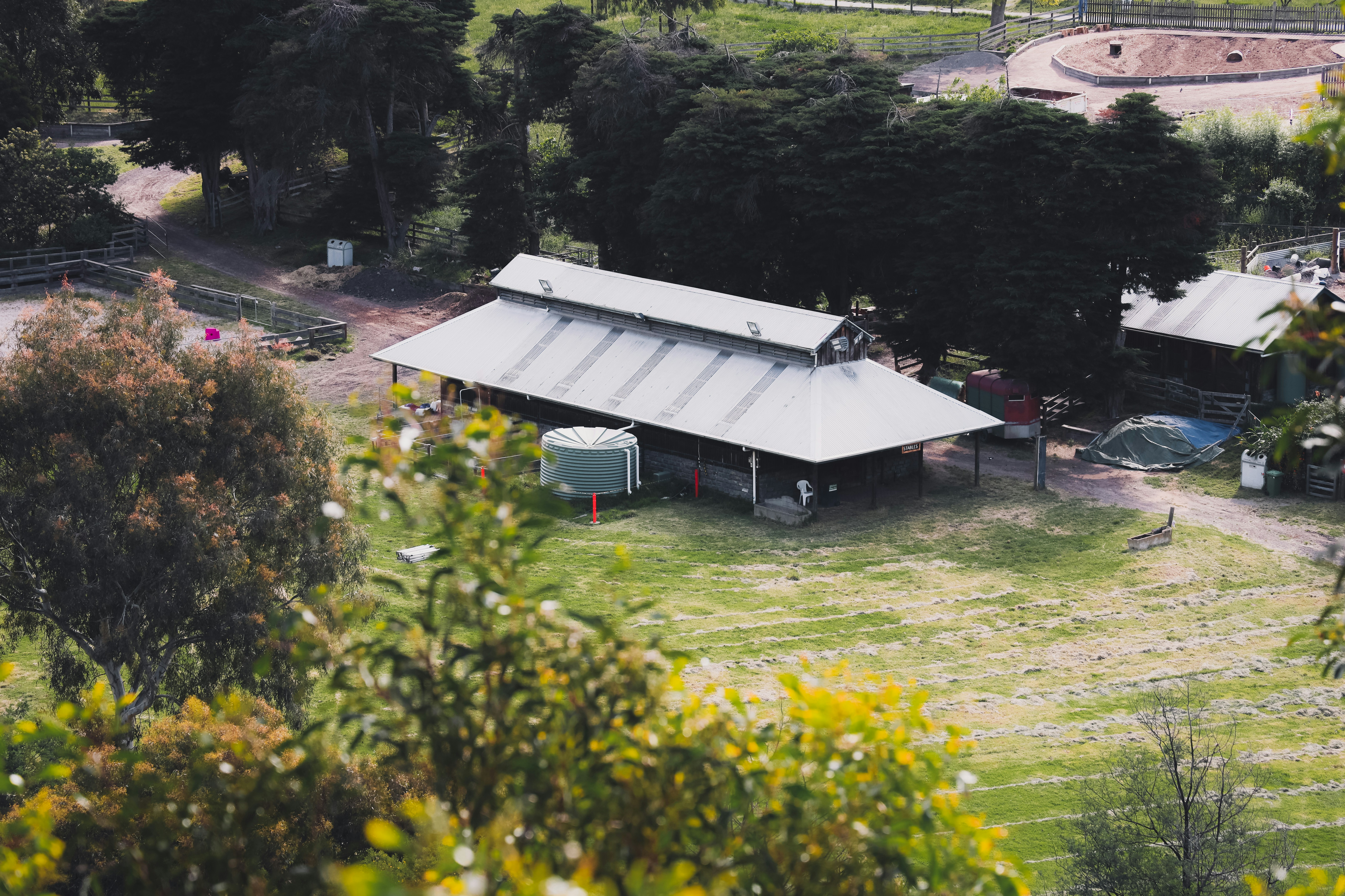 A rustic farmhouse nestled in a verdant landscape, surrounded by trees and open fields. The setting reflects a tranquil rural lifestyle.