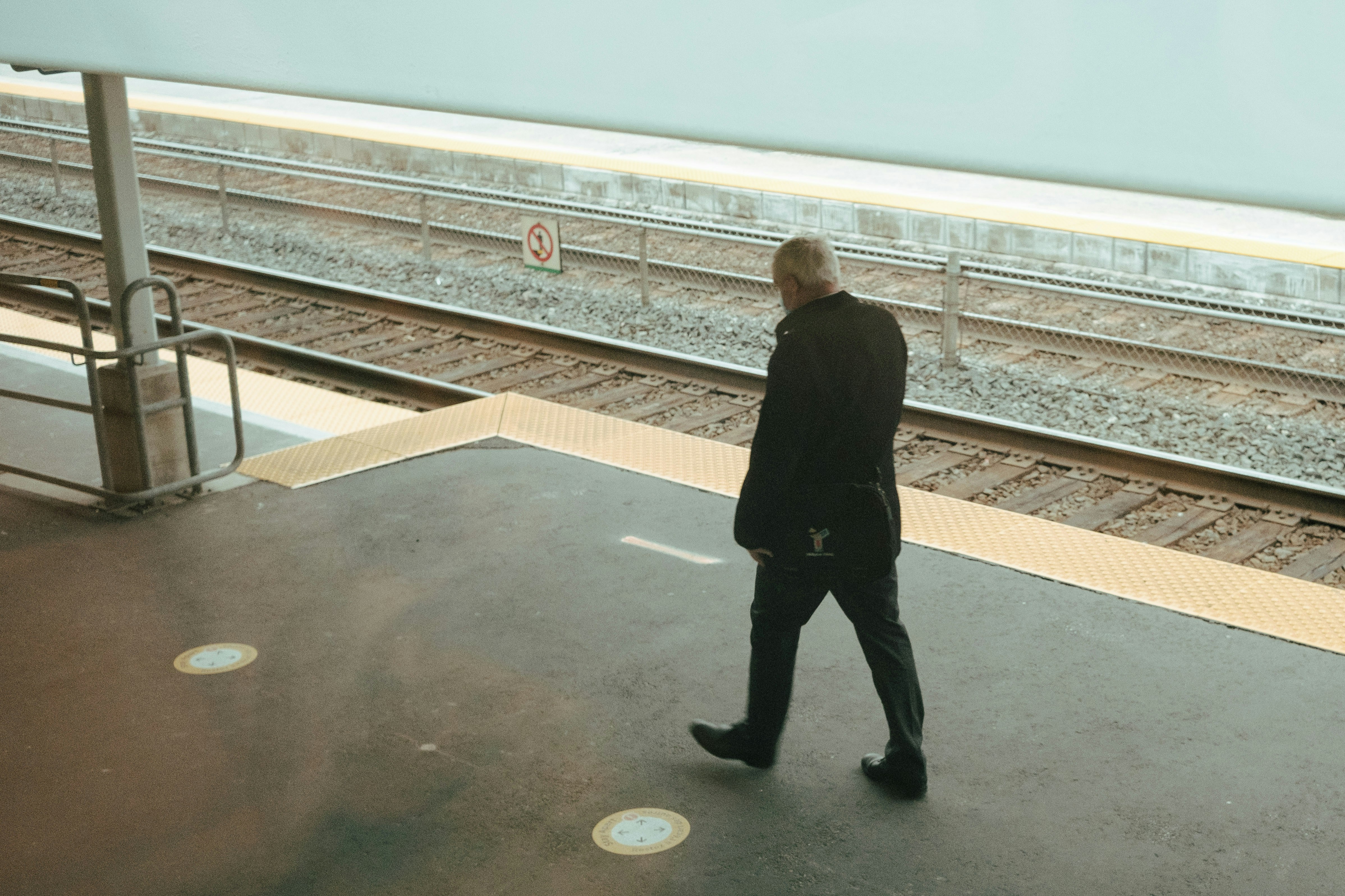 Solo commuter strides along a sunlit platform edge