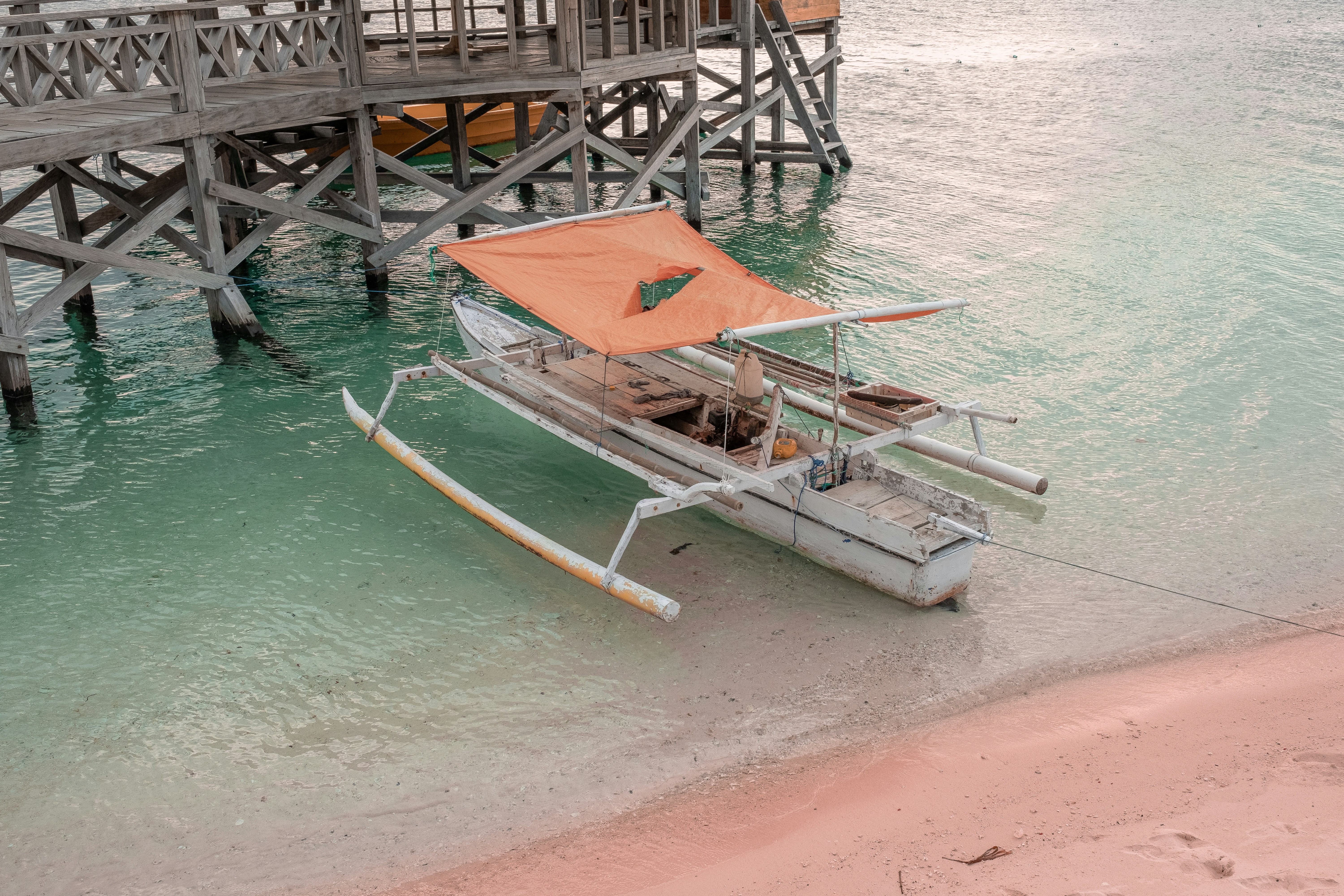 Orange Canopy Outrigger by a Wooden Pier on Turquoise Waters