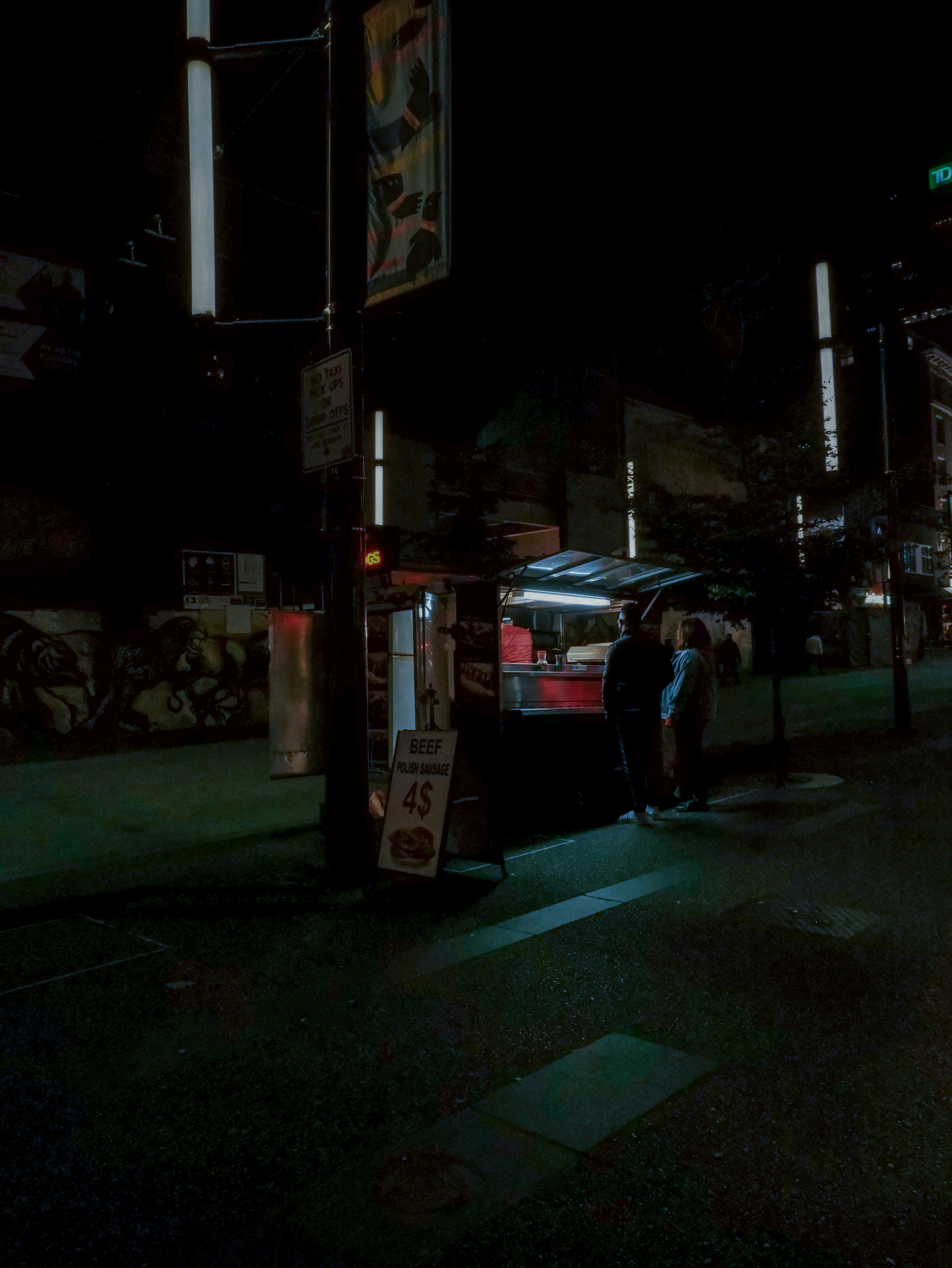 Neon Glow at a Night Street Cart: Two Figures Under Shelter