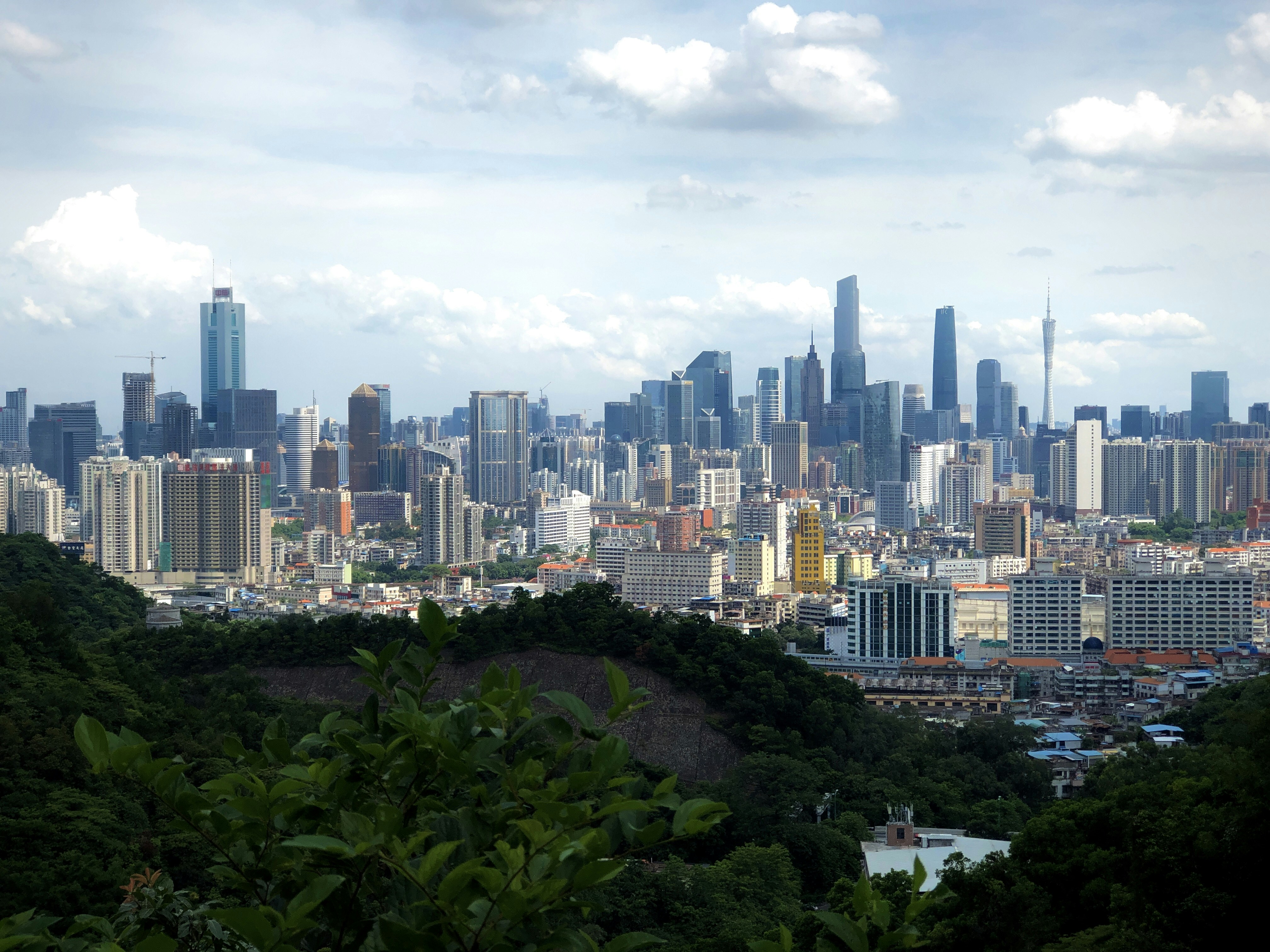 Guangzhou city, China. Skyscraper view from BaiyunShan Mountain | city skyline under white cloudy sky during daytime