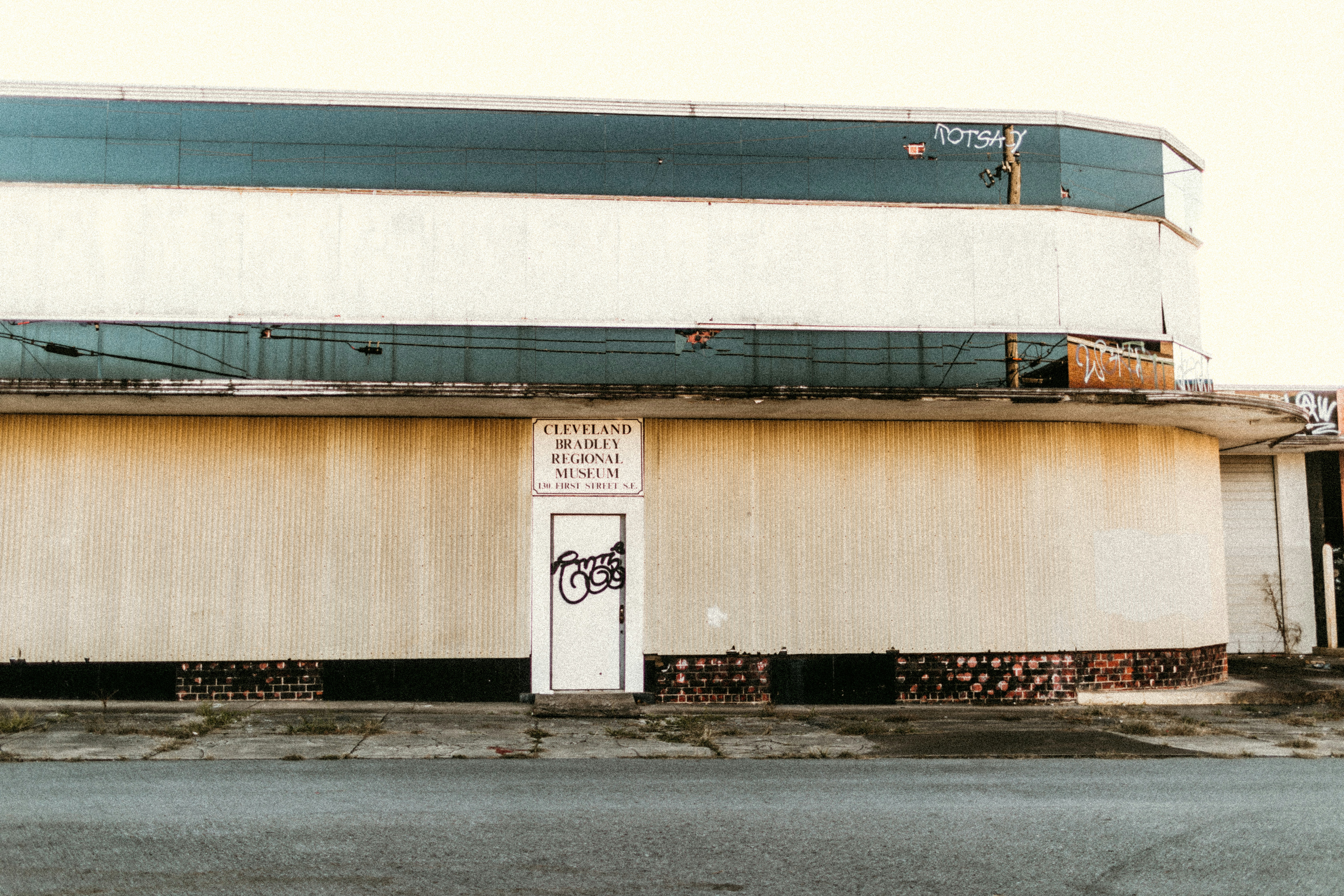 Dilapidated building with graffiti and a weathered sign, reflecting urban decay and forgotten stories. The structure's peeling paint and empty doorway evoke a sense of nostalgia.