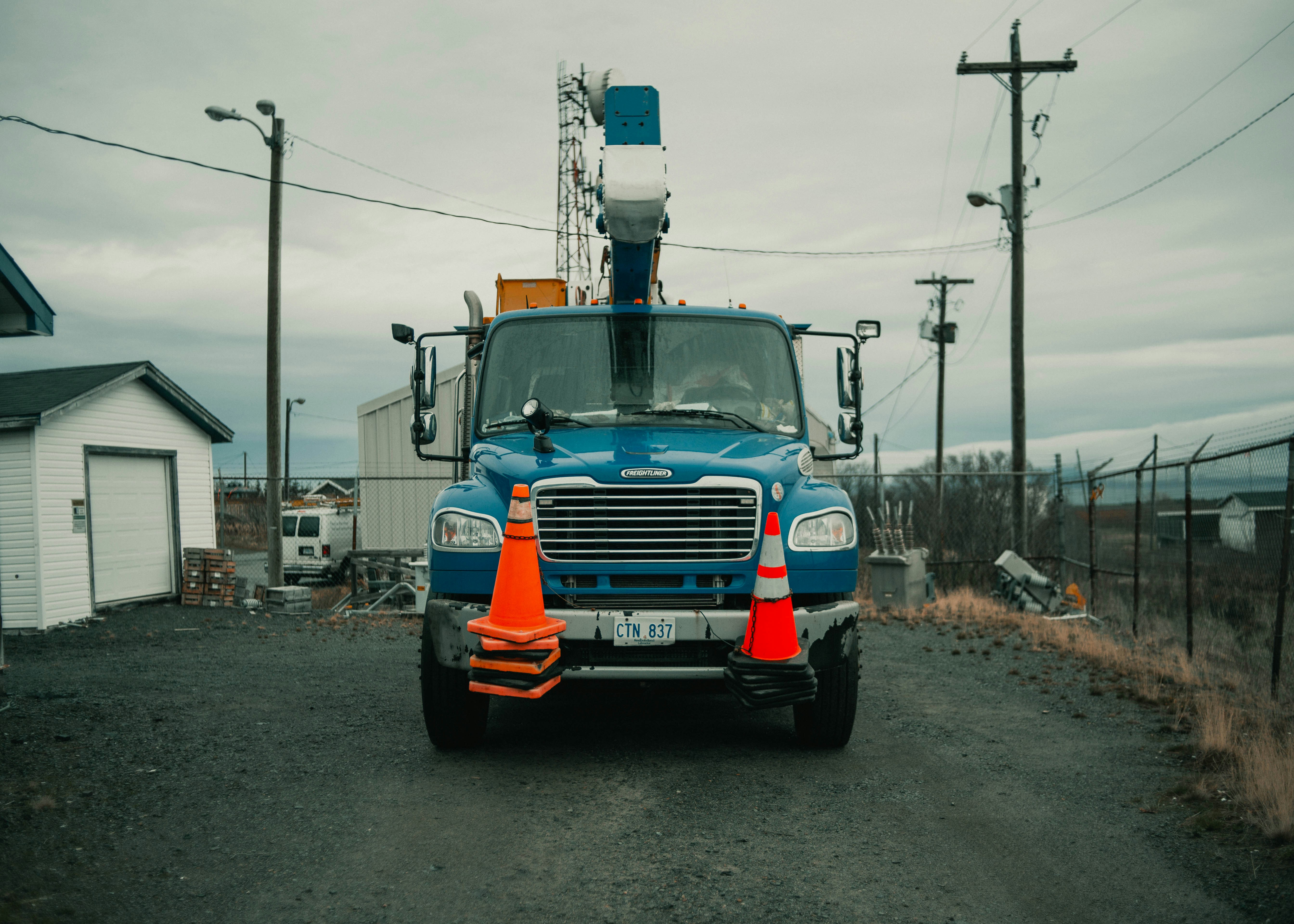 Blue Bucket Truck Anchored in a Grim Industrial Yard Under Overcast Skies