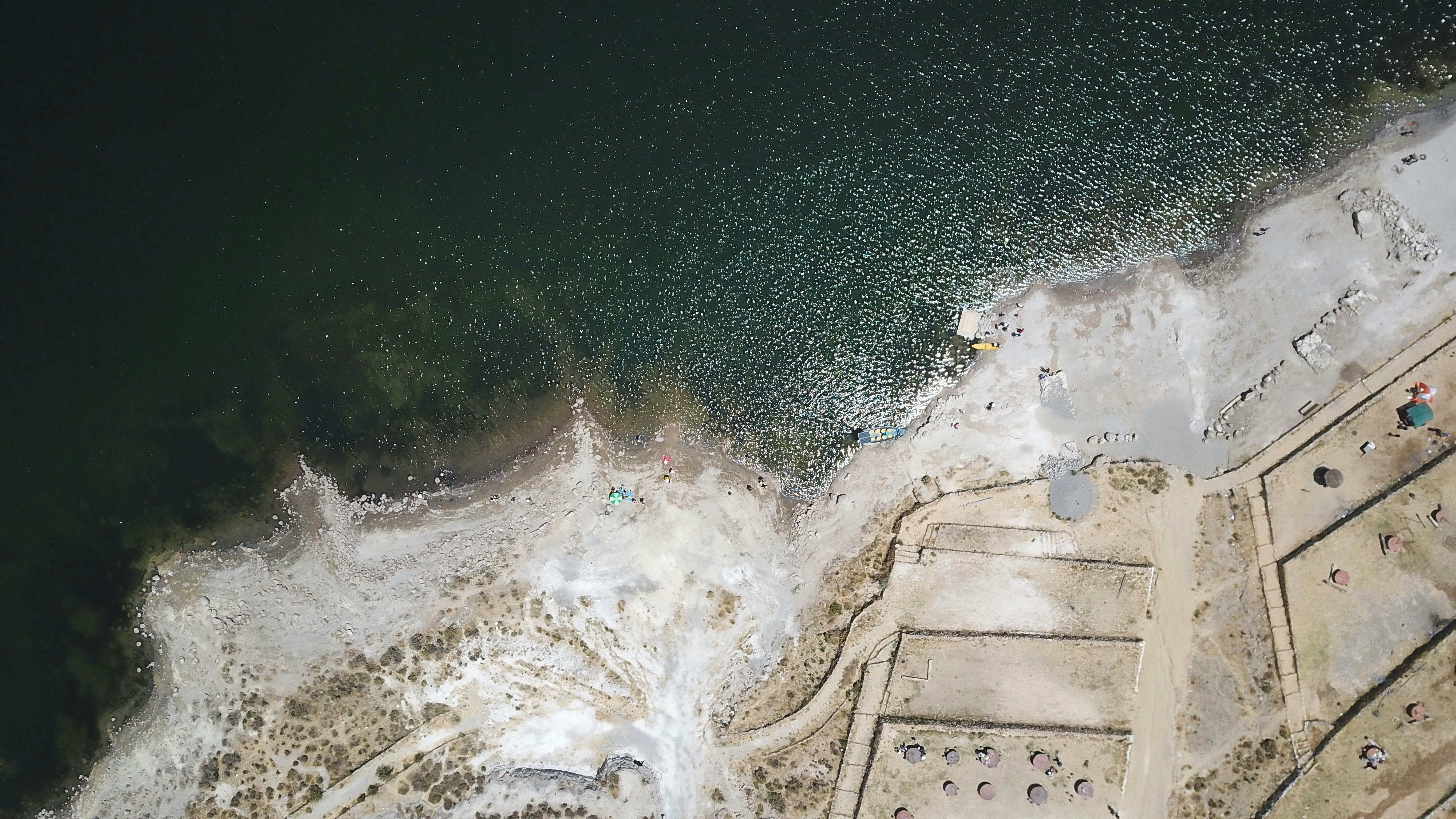 Aerial view of a rugged shoreline meeting dark waters, with visible land formations and vegetation.
