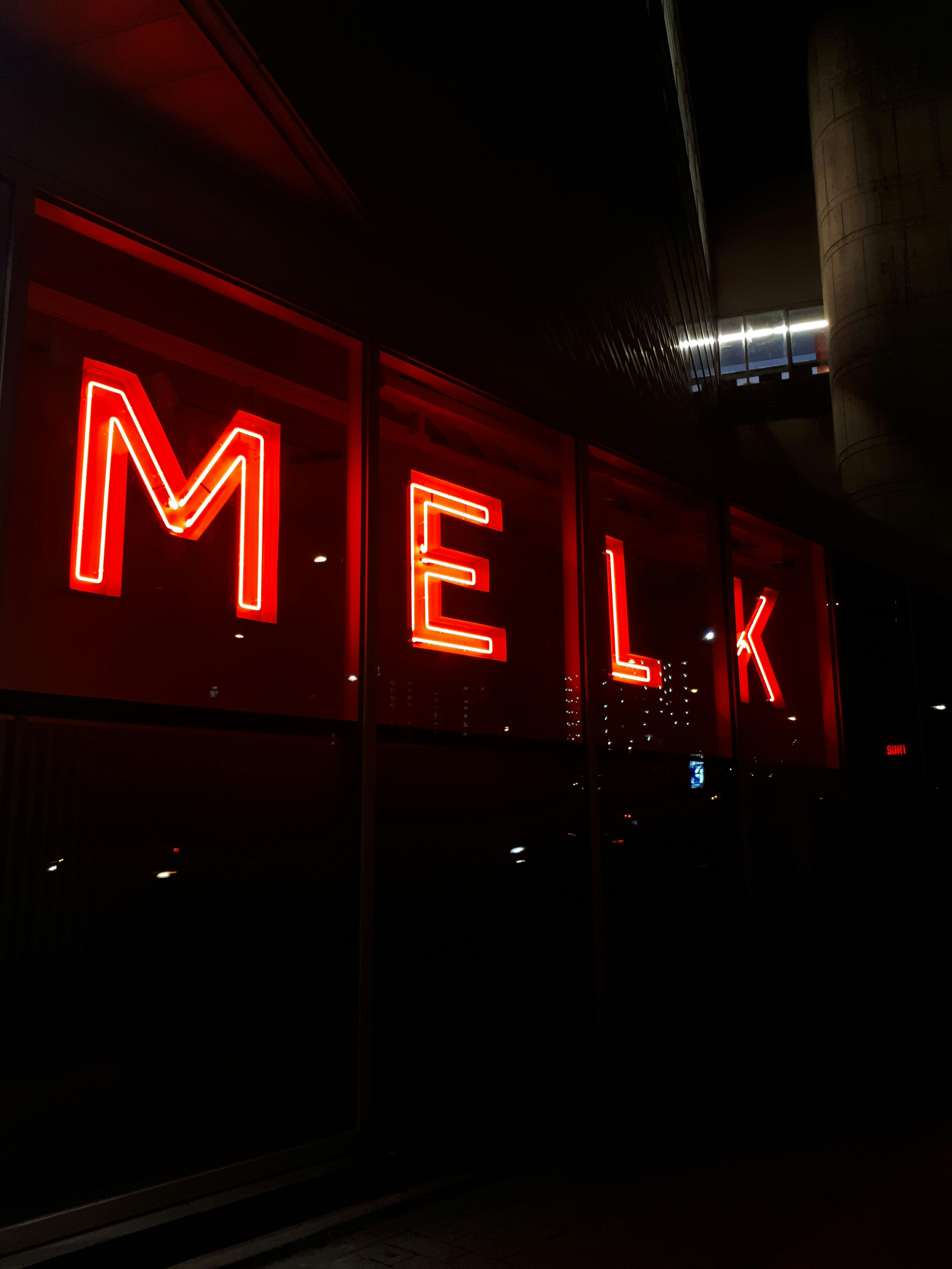 MELK Neon on Dark Glass: Reflections in a Quiet Night