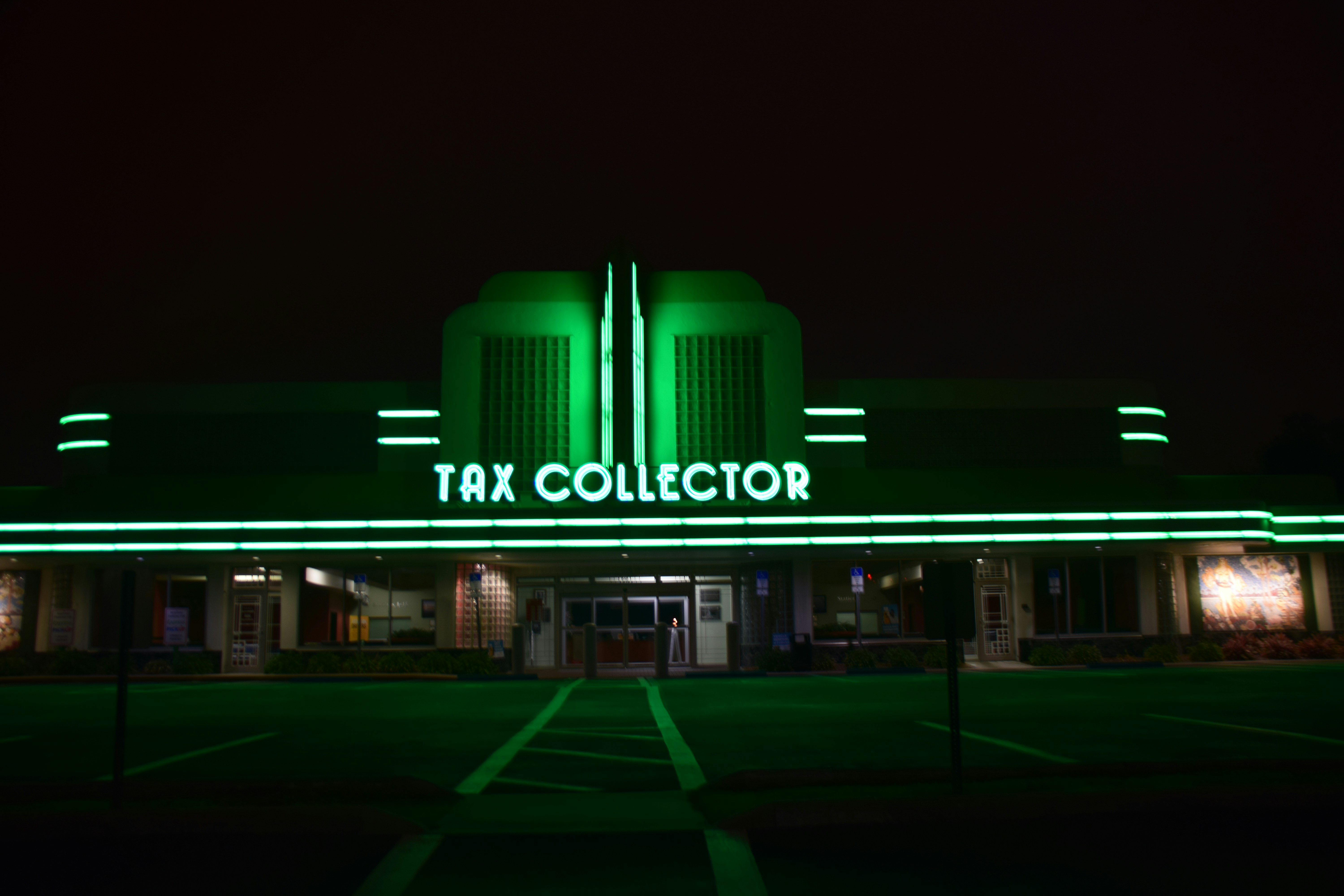 A large building with a neon sign that says tax collector photo – Free ...