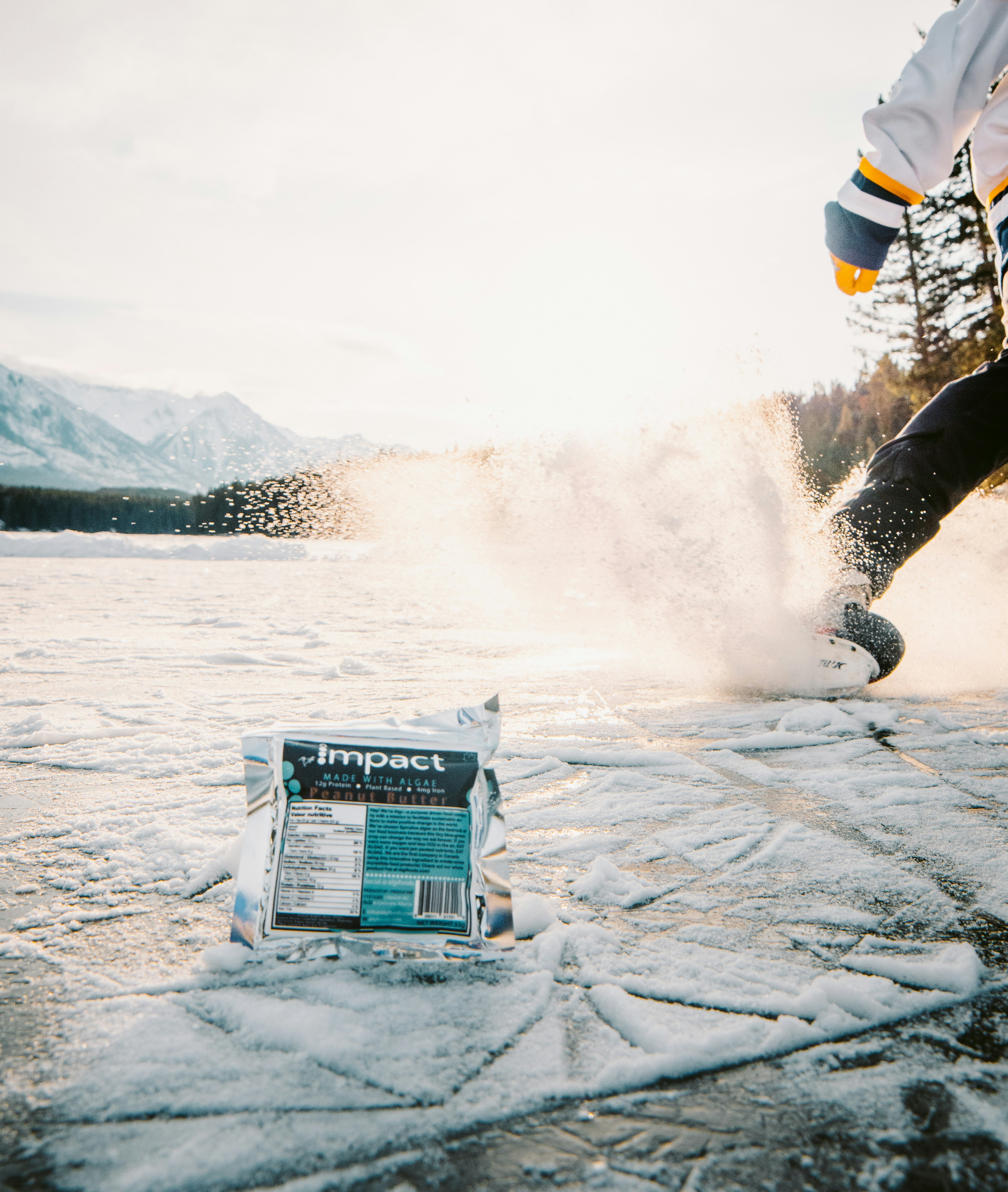 Ice Spray Momentum: Snowboarder Carves a Wake on a Frozen Lake with an Impact Package in View