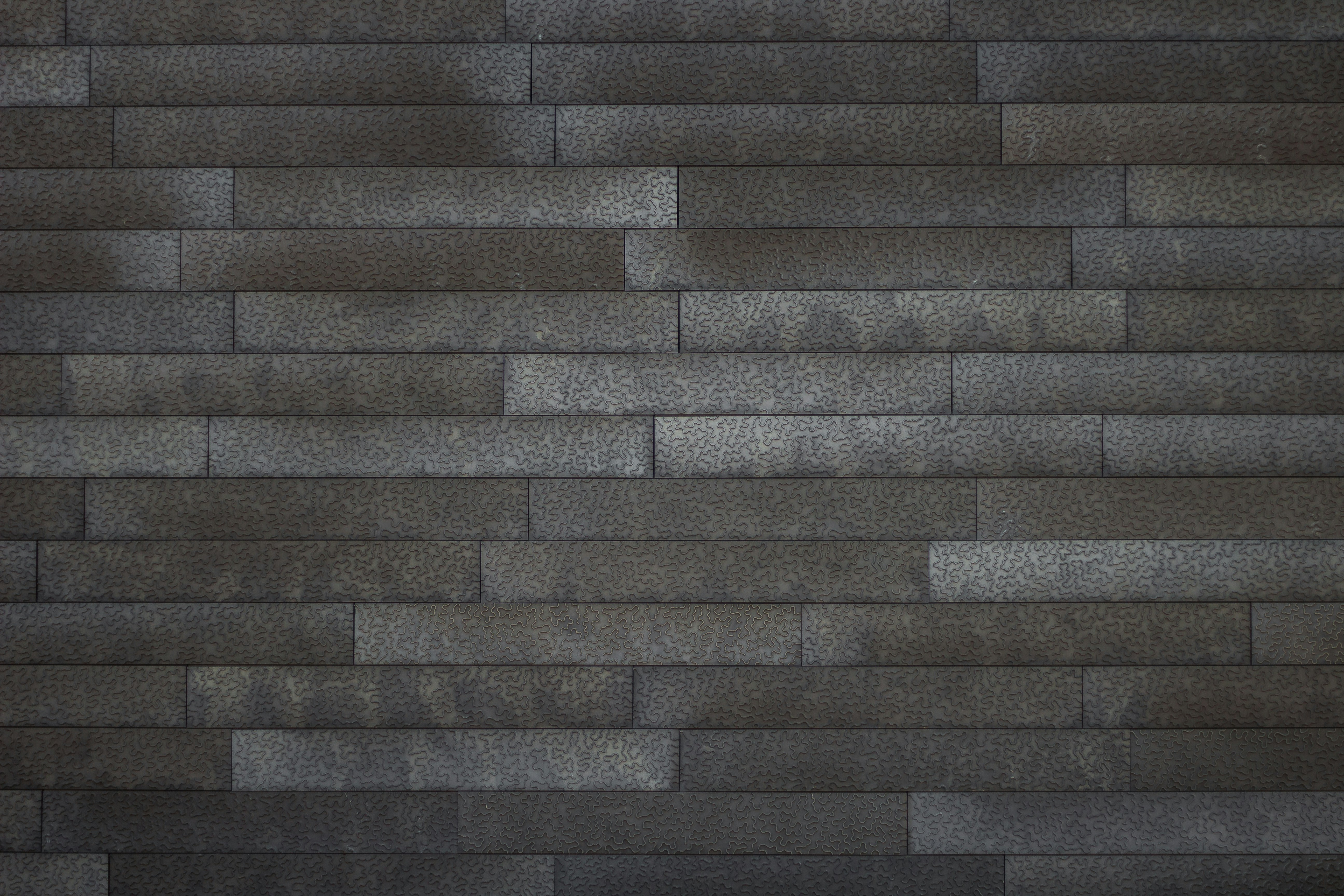 Close-up view of a dark, textured wall featuring horizontal stone tiles arranged in a sleek pattern.