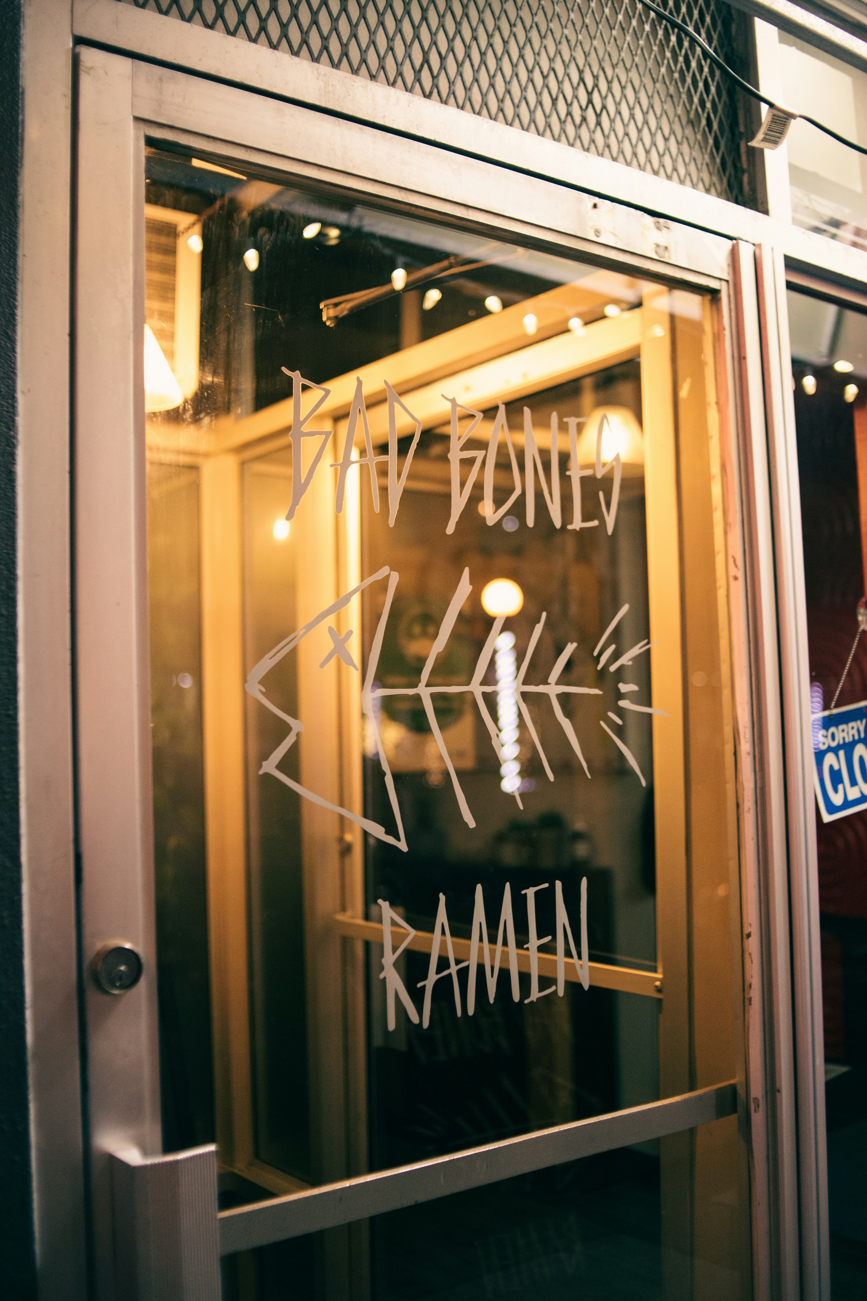 Glass Door Graffiti: Neon Lights Reflected in a Cozy Urban Shopfront