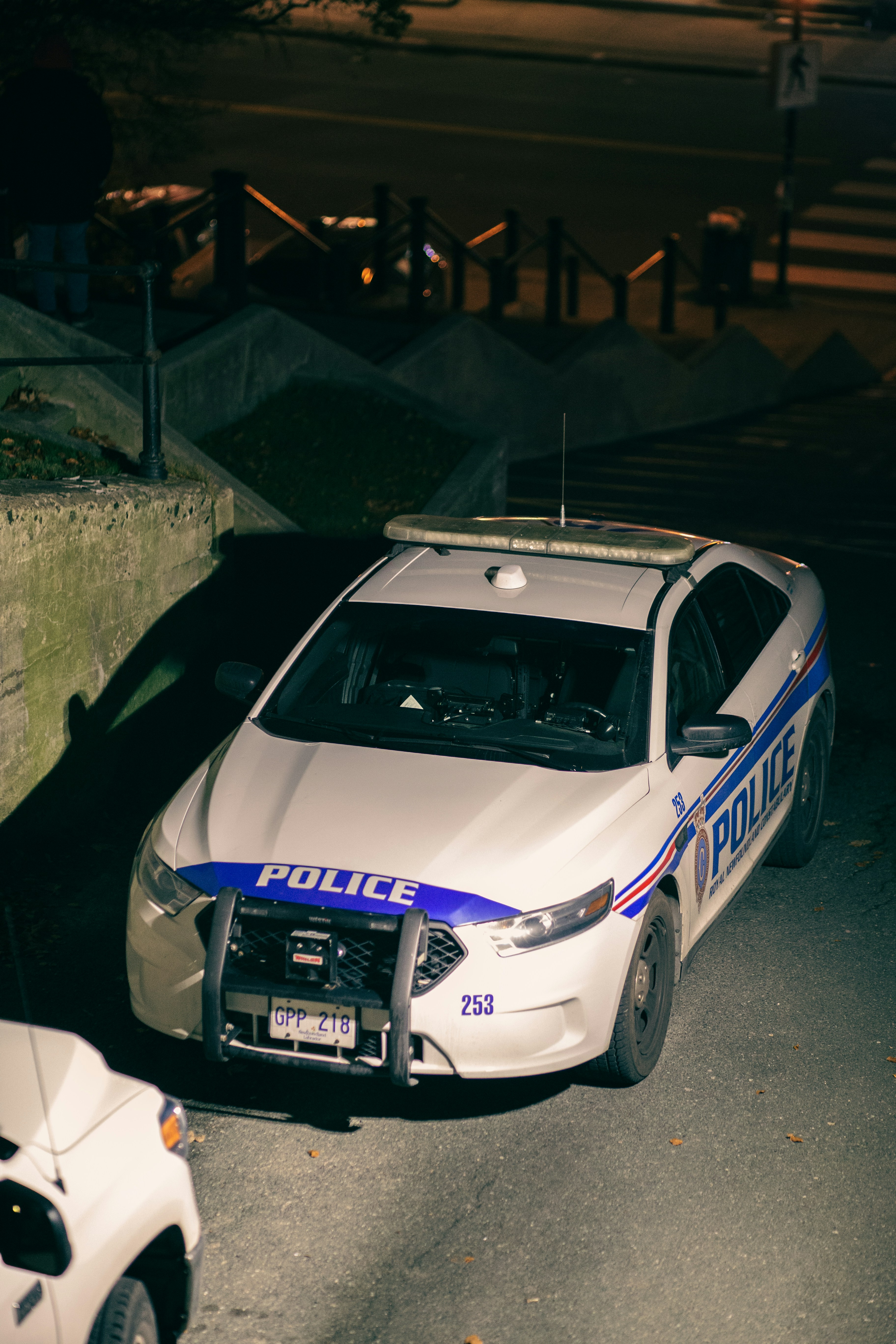 Night Patrol by the Stairs: A White Police Cruiser Anchors a Dim City Block