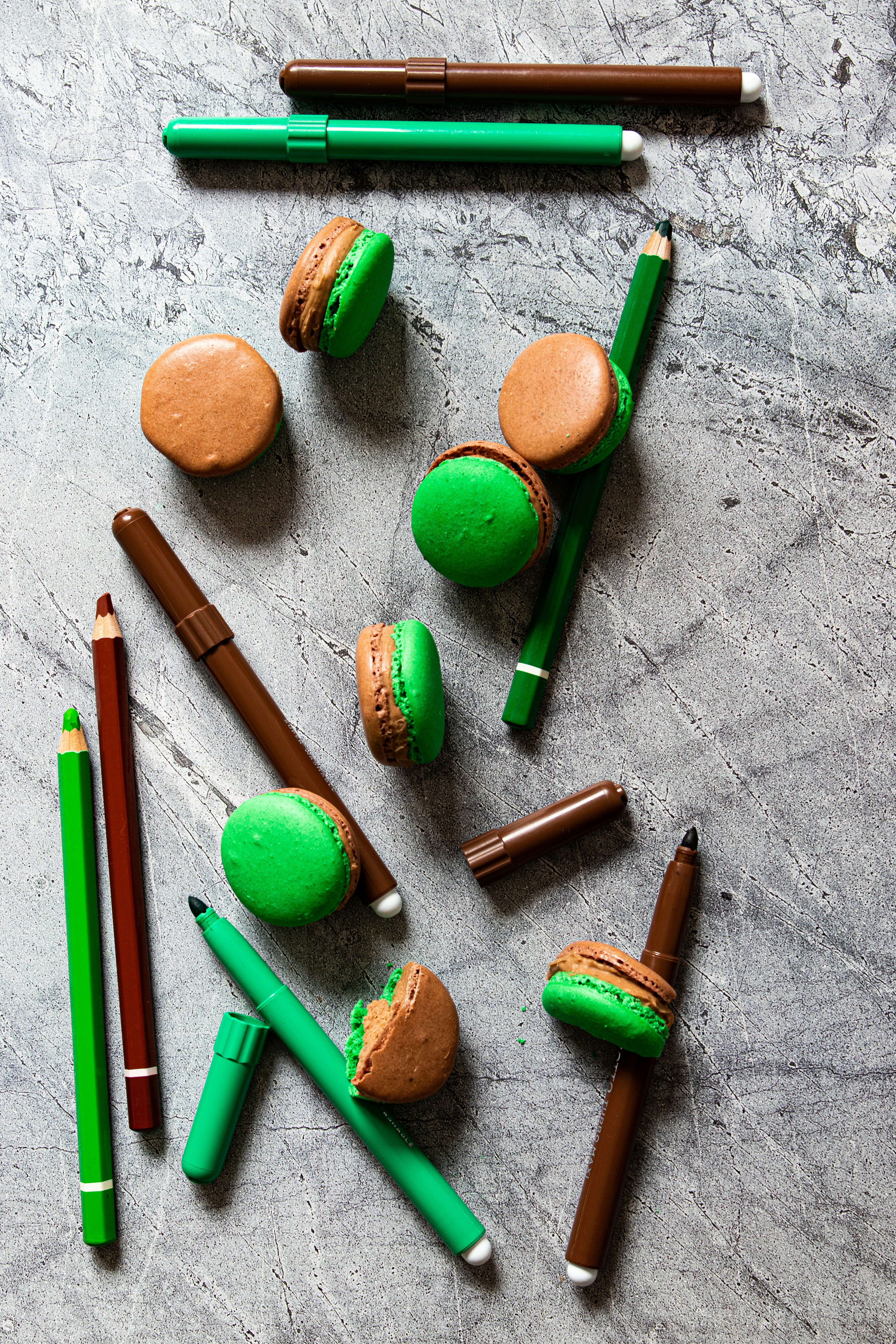 Verdant Macaron Mosaic: Green Treats Amid Graphite on a Concrete Surface