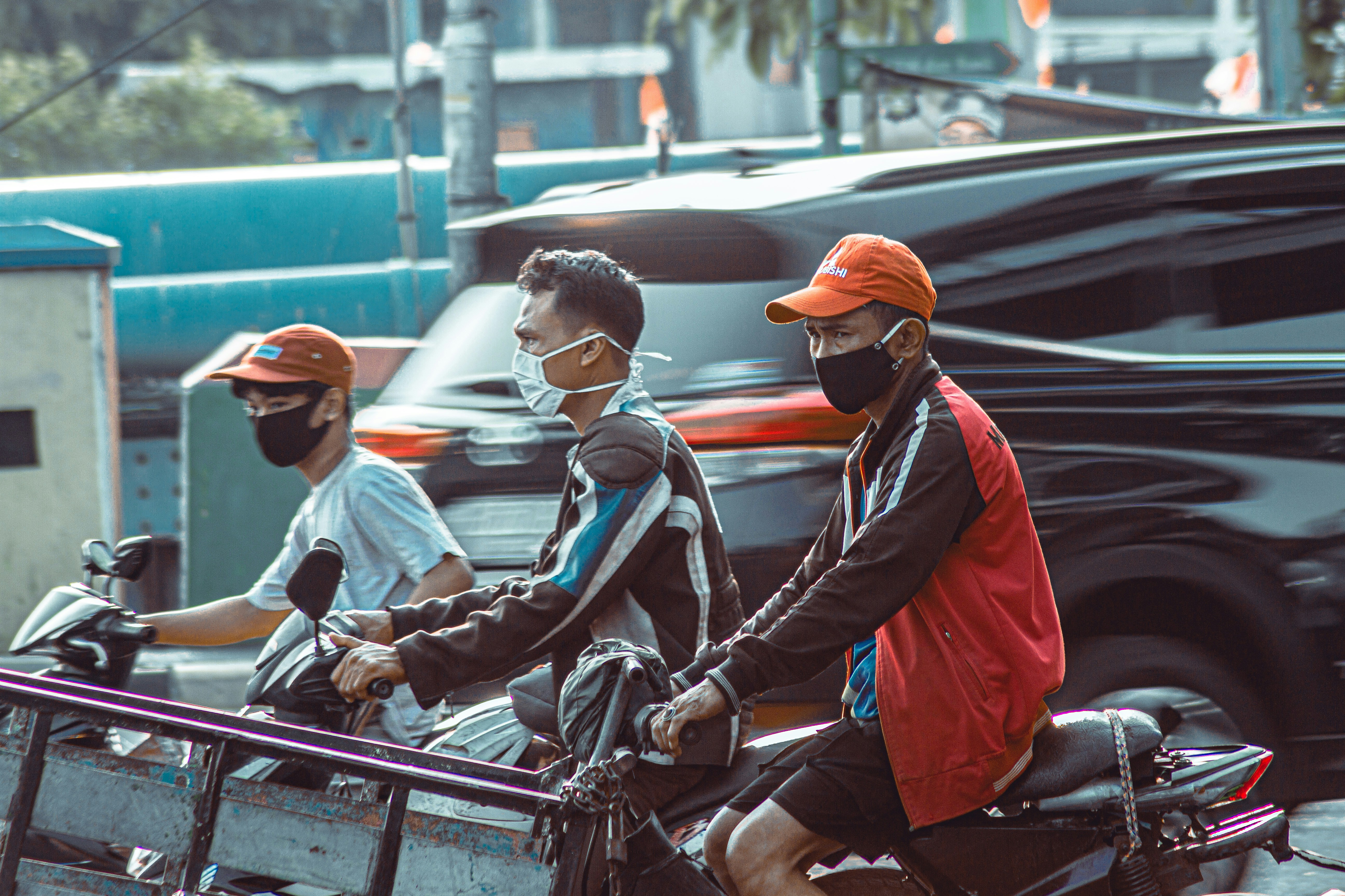 Three motorcyclists navigate a busy street, showcasing urban life and the importance of mobility. The scene captures a moment of daily commute amidst the hustle and bustle.