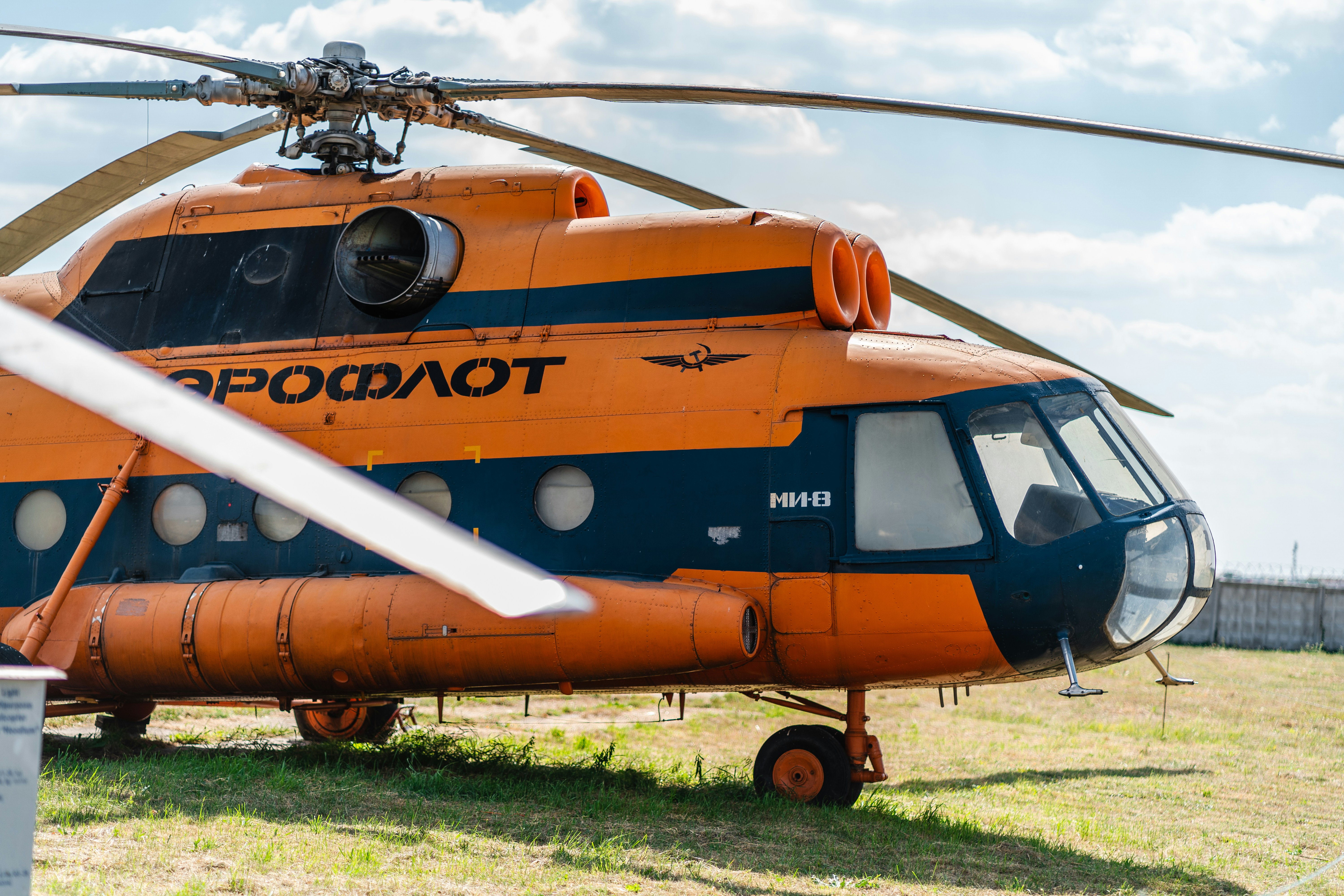 Orange Mi-8 on a Grassy Field Under a Bright Sky