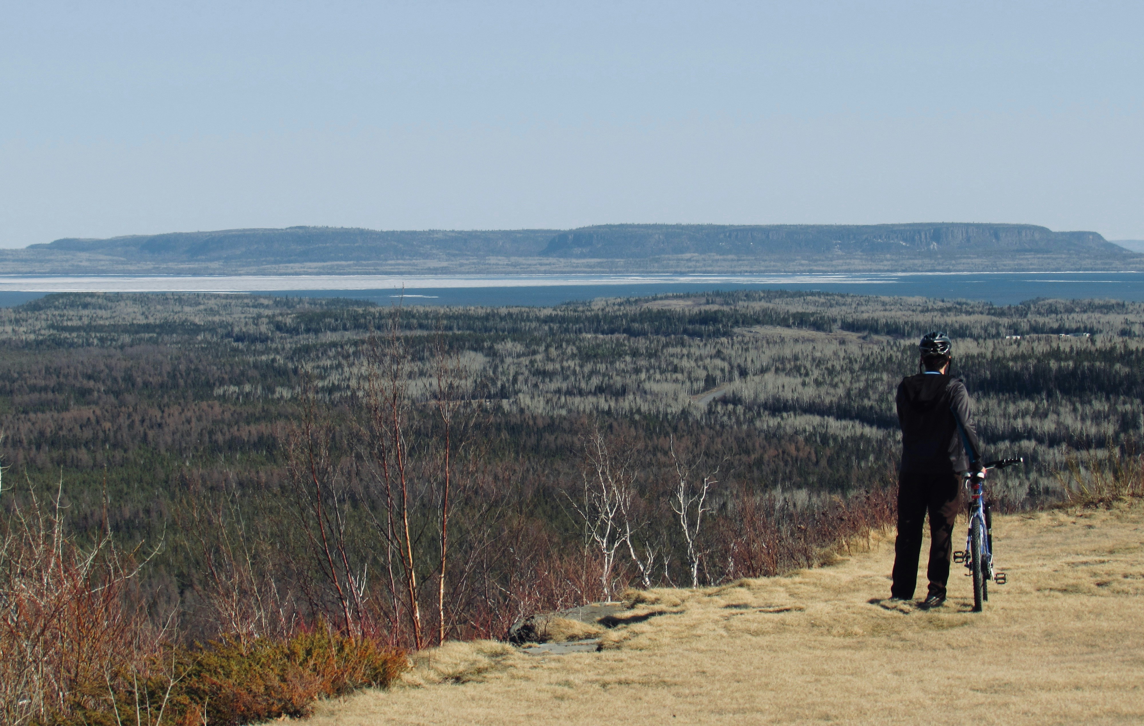 Ridgeward Solitude: A lone cyclist at the overlook gazing toward a quiet lake