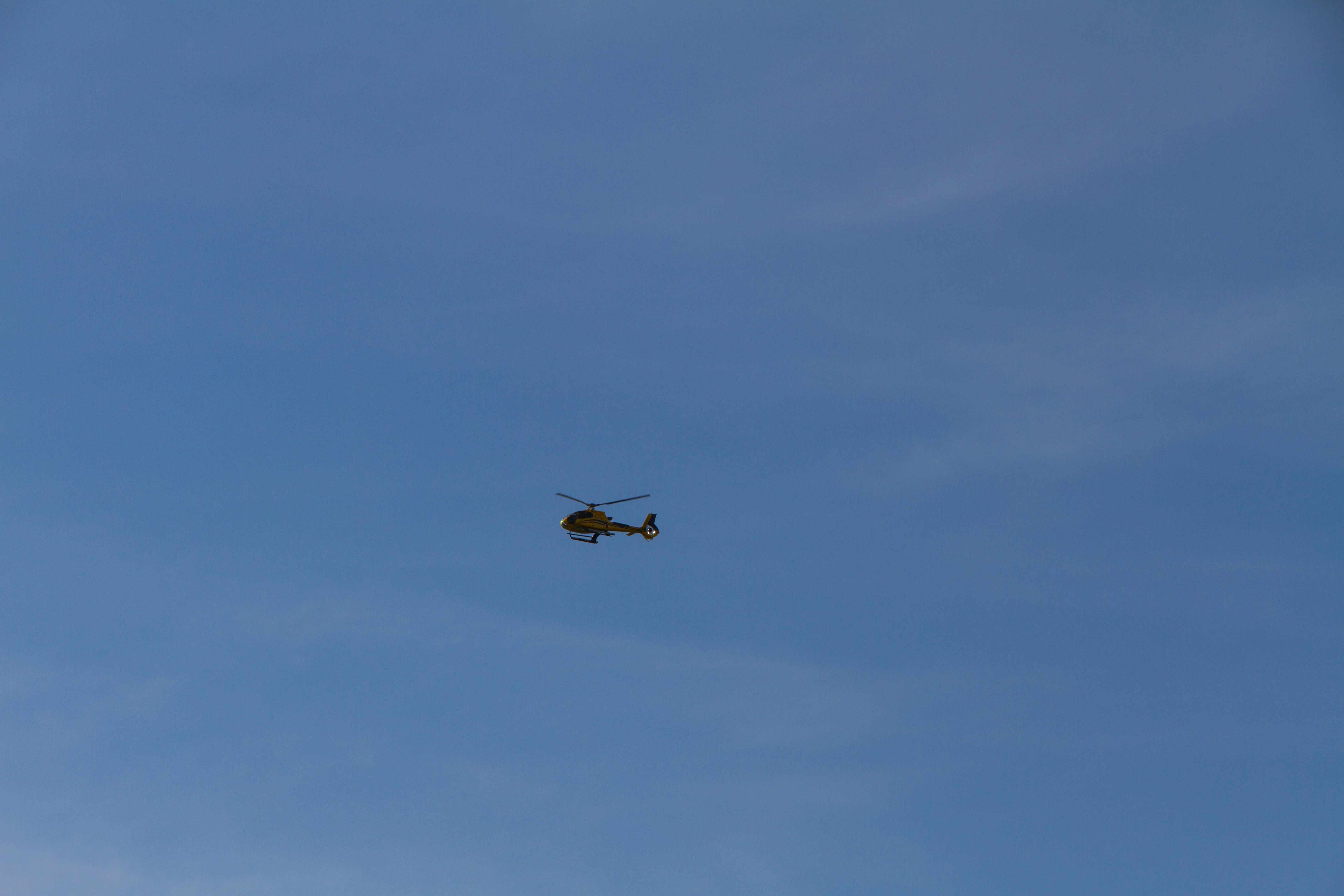 A helicopter glides gracefully through a clear blue sky, showcasing its flight capabilities against a serene backdrop.