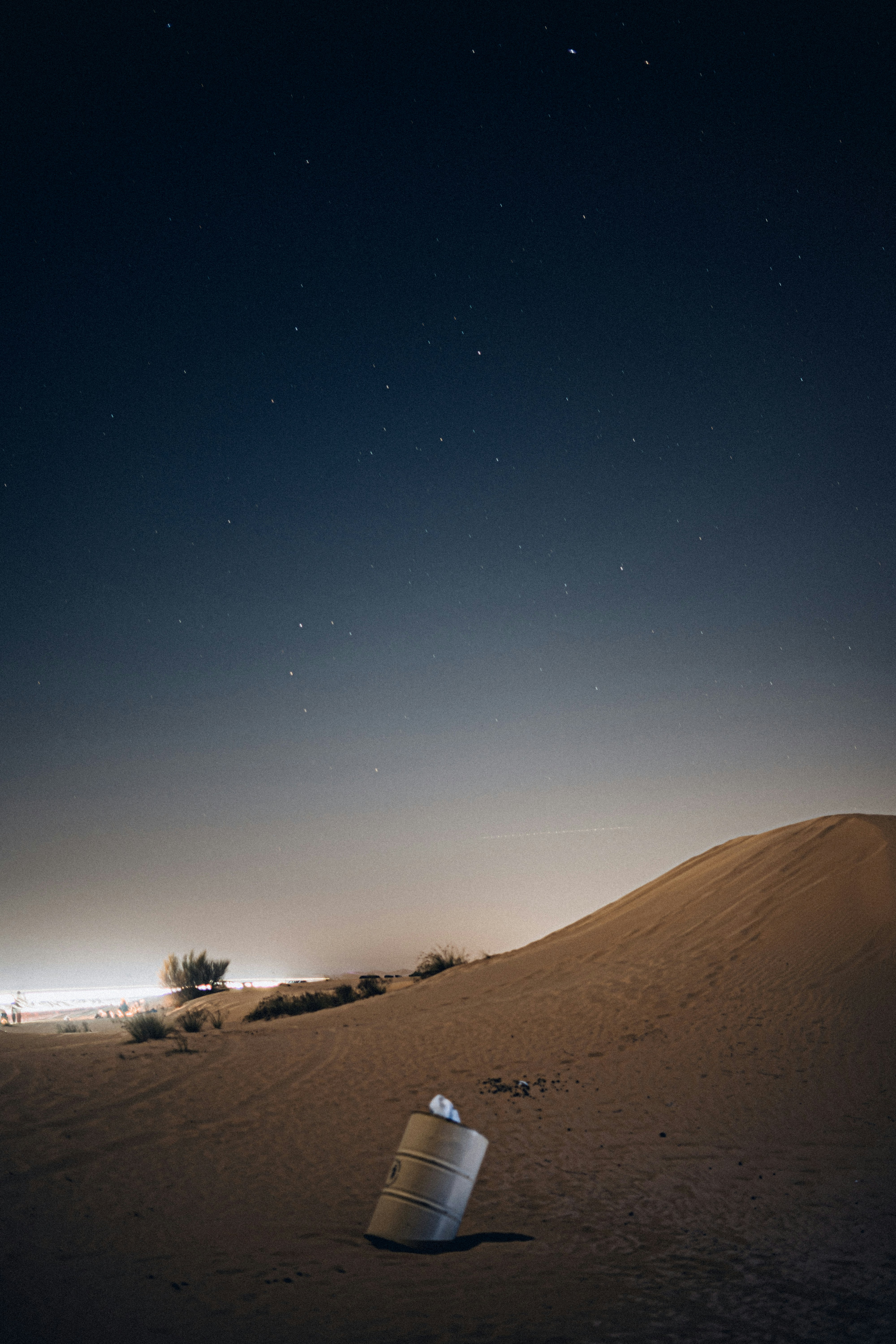 Desert Nightfall: A Lone Waste Barrel Under A Starry Sky