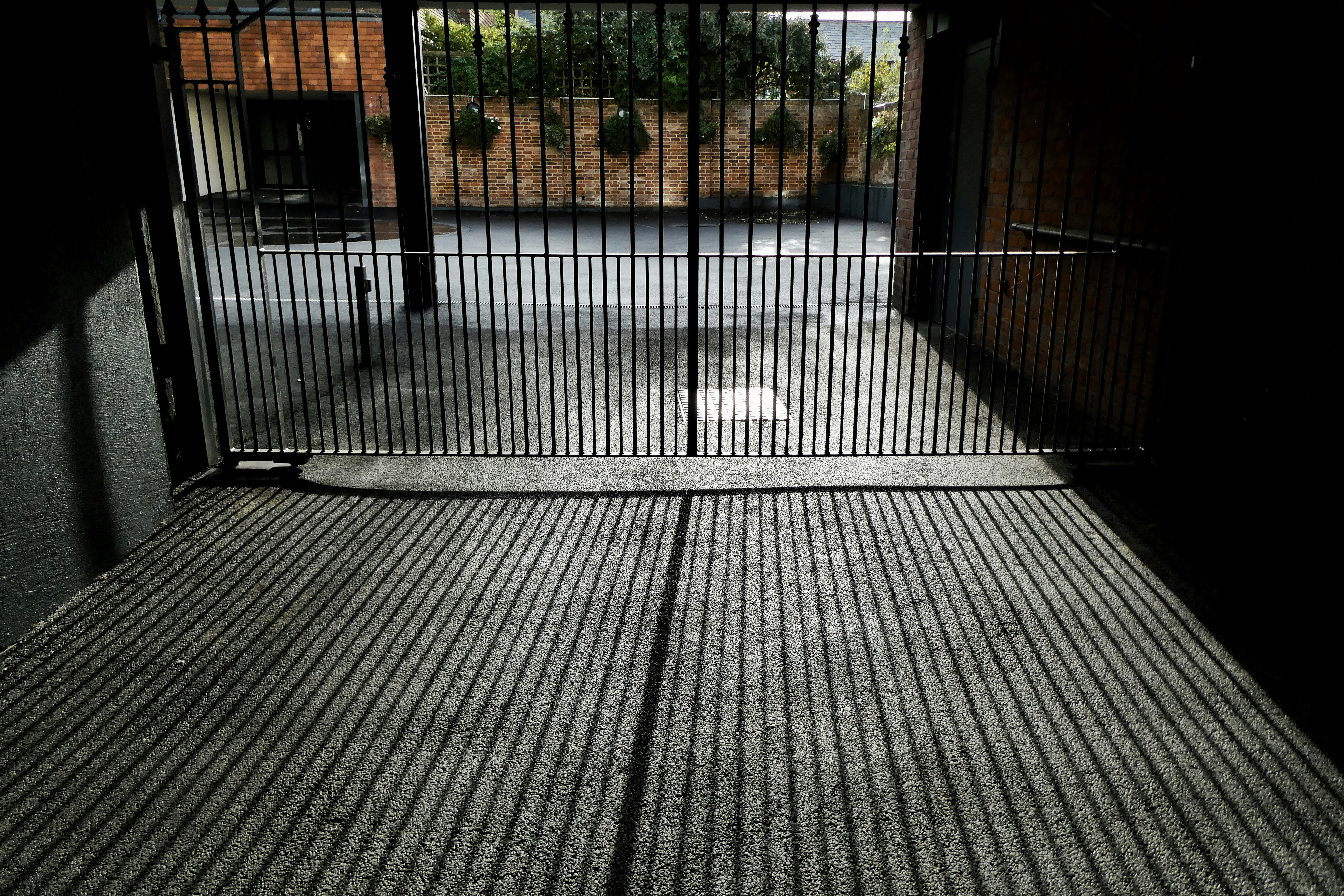 Threshold of Daylight: Striped Shadows Across a Gated Corridor
