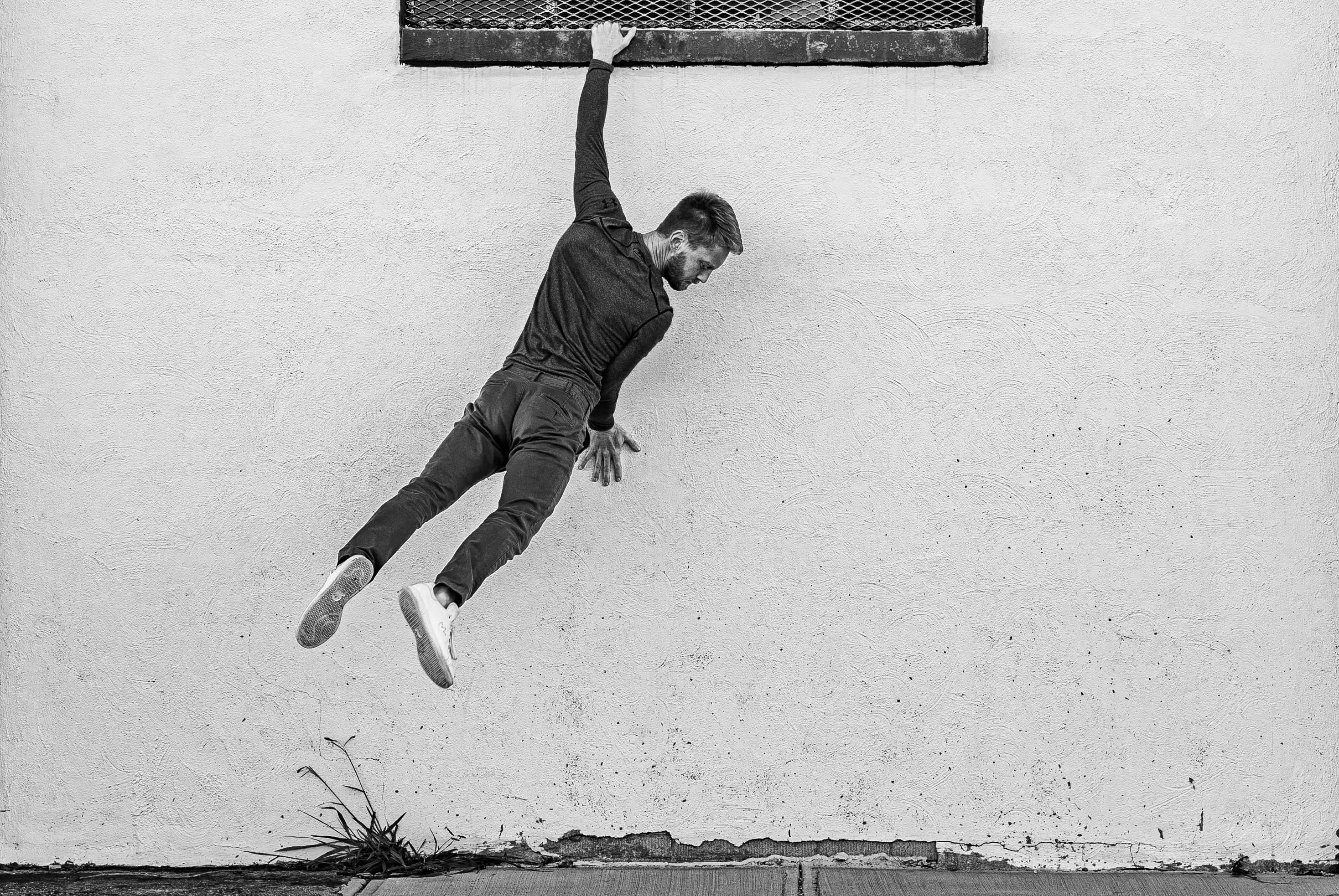 Midair Defiance: A Man Clings to a Wall