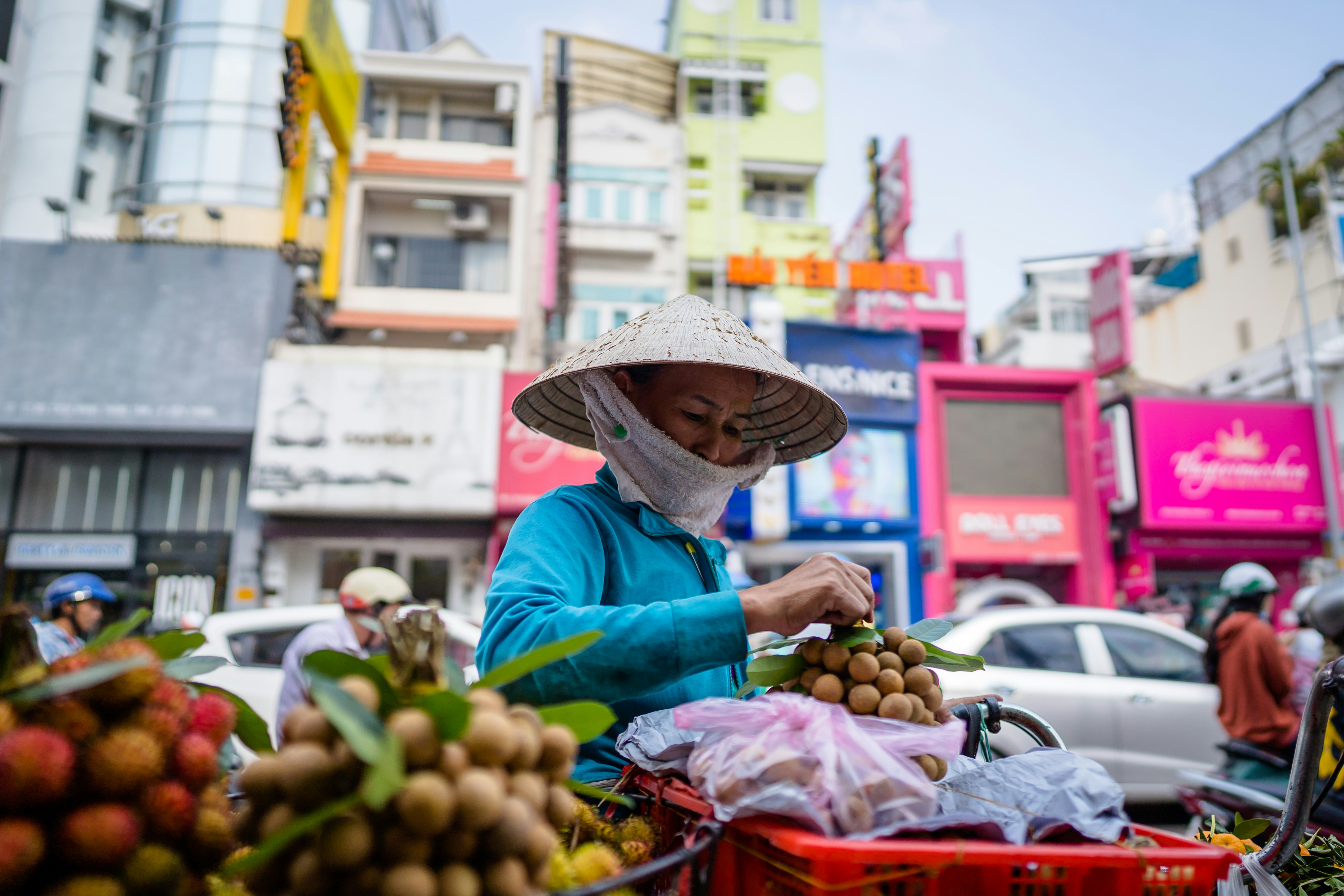 Vietnamese sellers wake up at 3am to be at the wet markets in time to  | woman in blue long sleeve shirt and brown straw hat holding red fruit