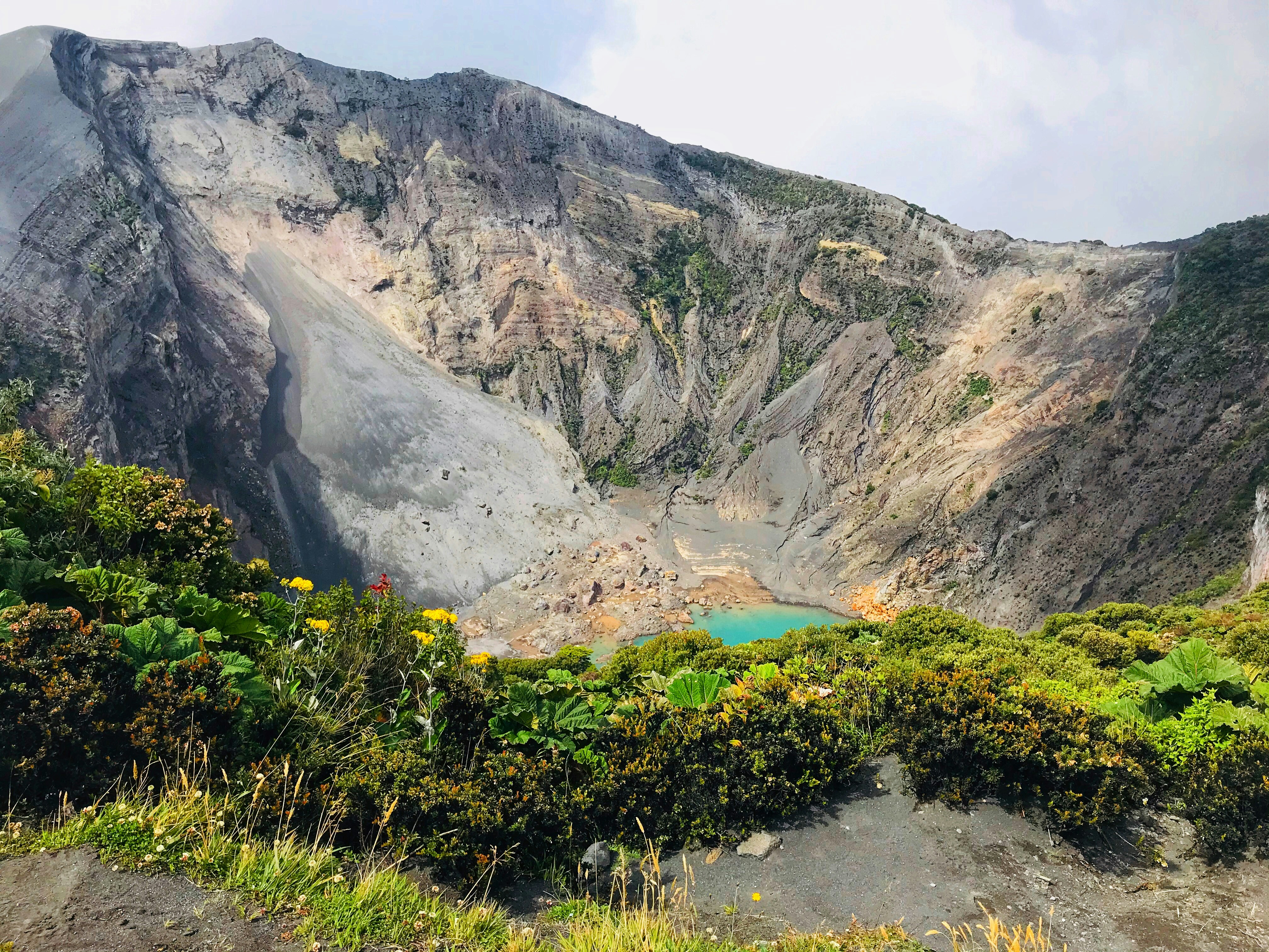 Volcanic crater with emerald green lake surrounded by lush vegetation.