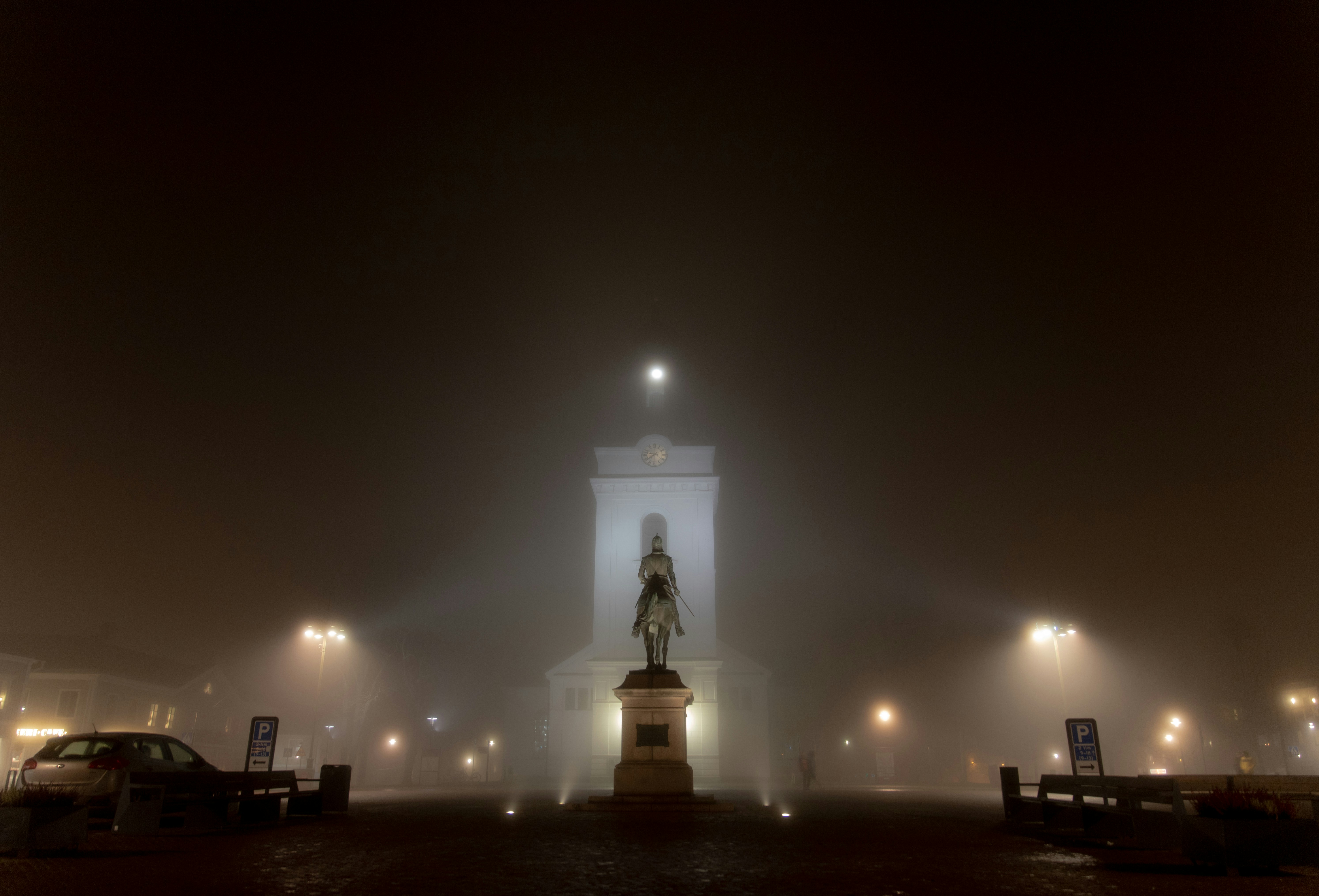 Veiled Sentinel: A Central Statue Emerges Through Night Fog