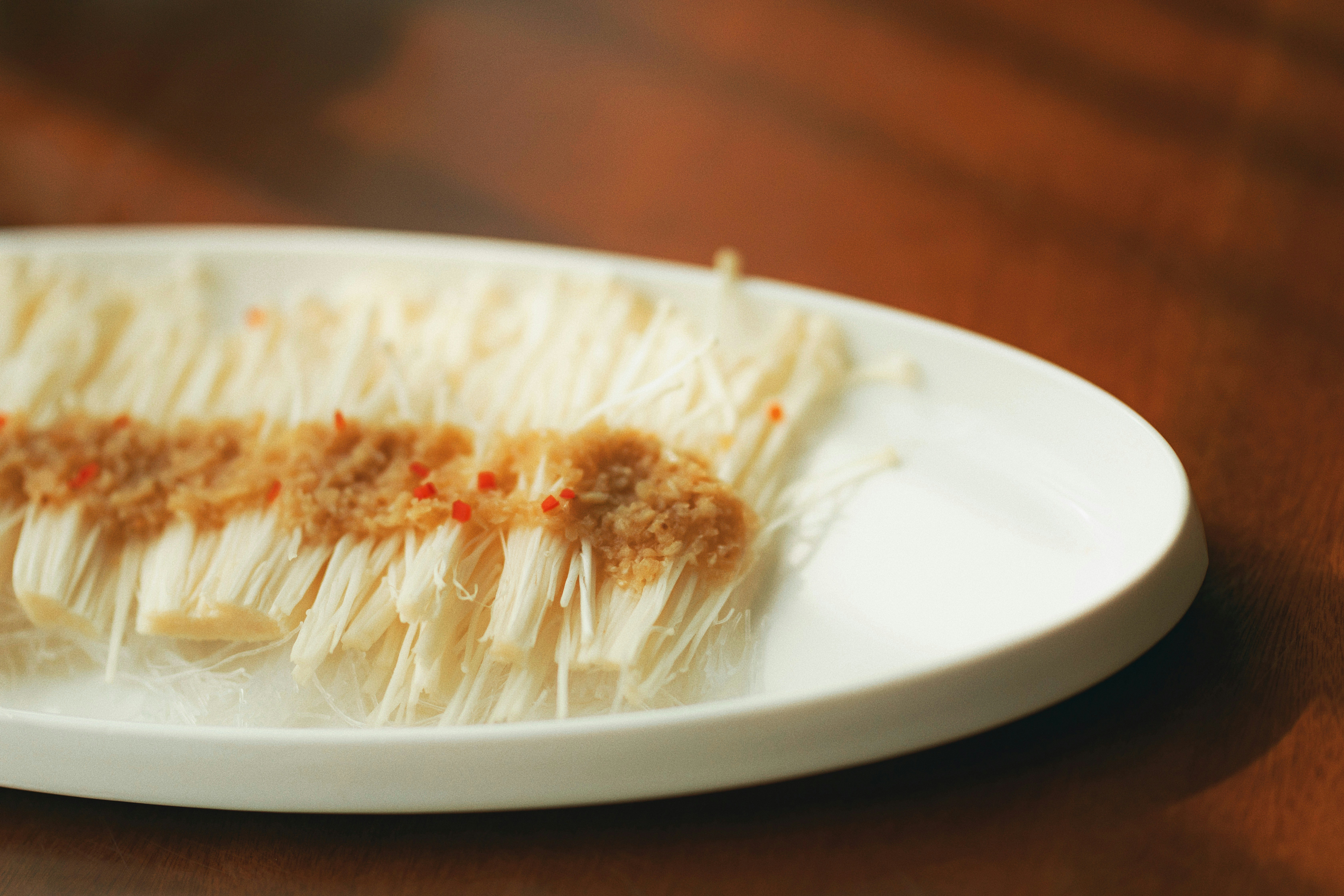 A plate of enoki mushrooms garnished with a savory sauce, showcasing the art of minimalistic cuisine.