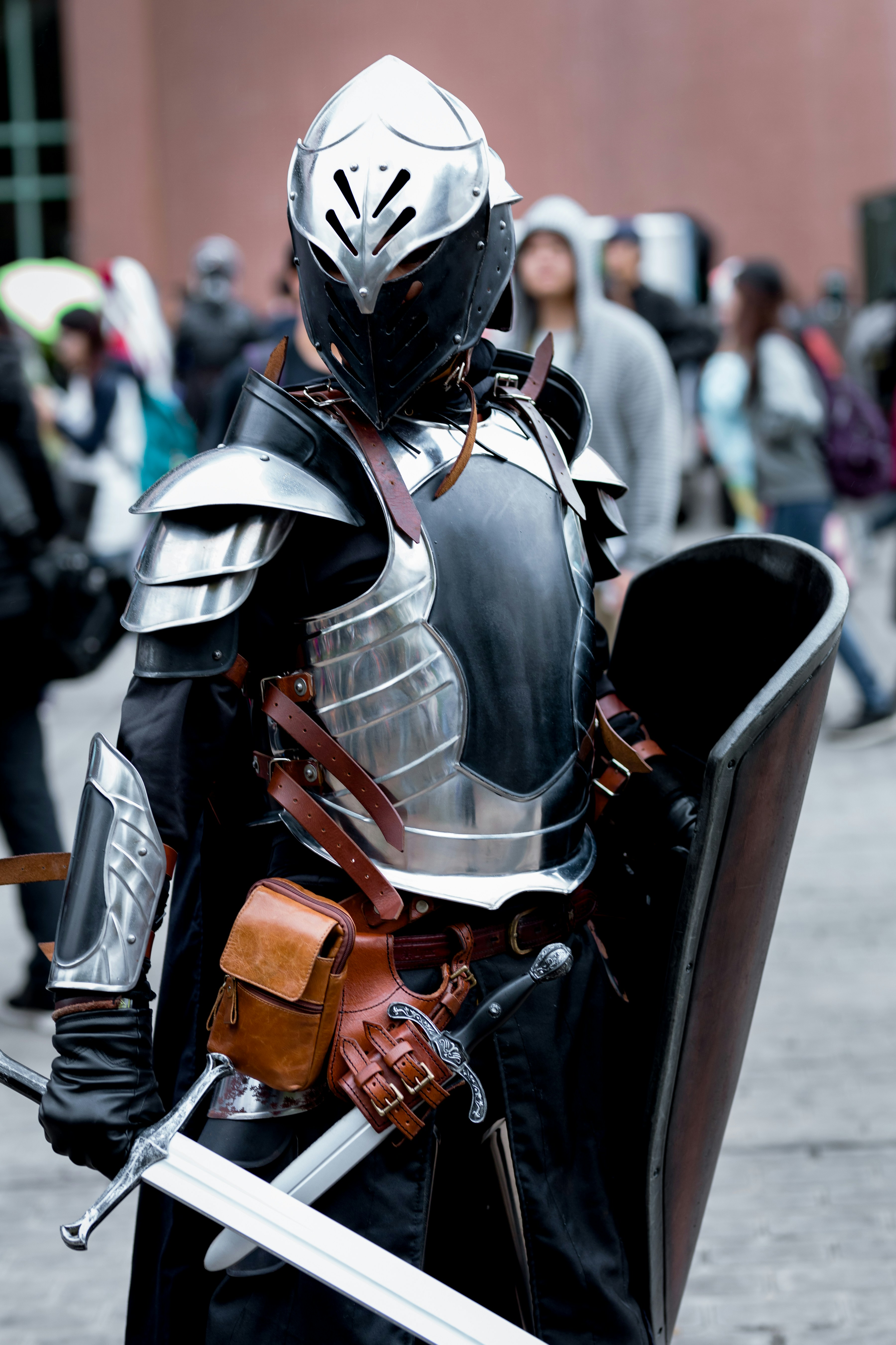 A knight in intricate armor stands confidently, wielding a sword and shield amidst a bustling crowd. The detailed craftsmanship of the armor reflects a blend of historical and fantastical elements.