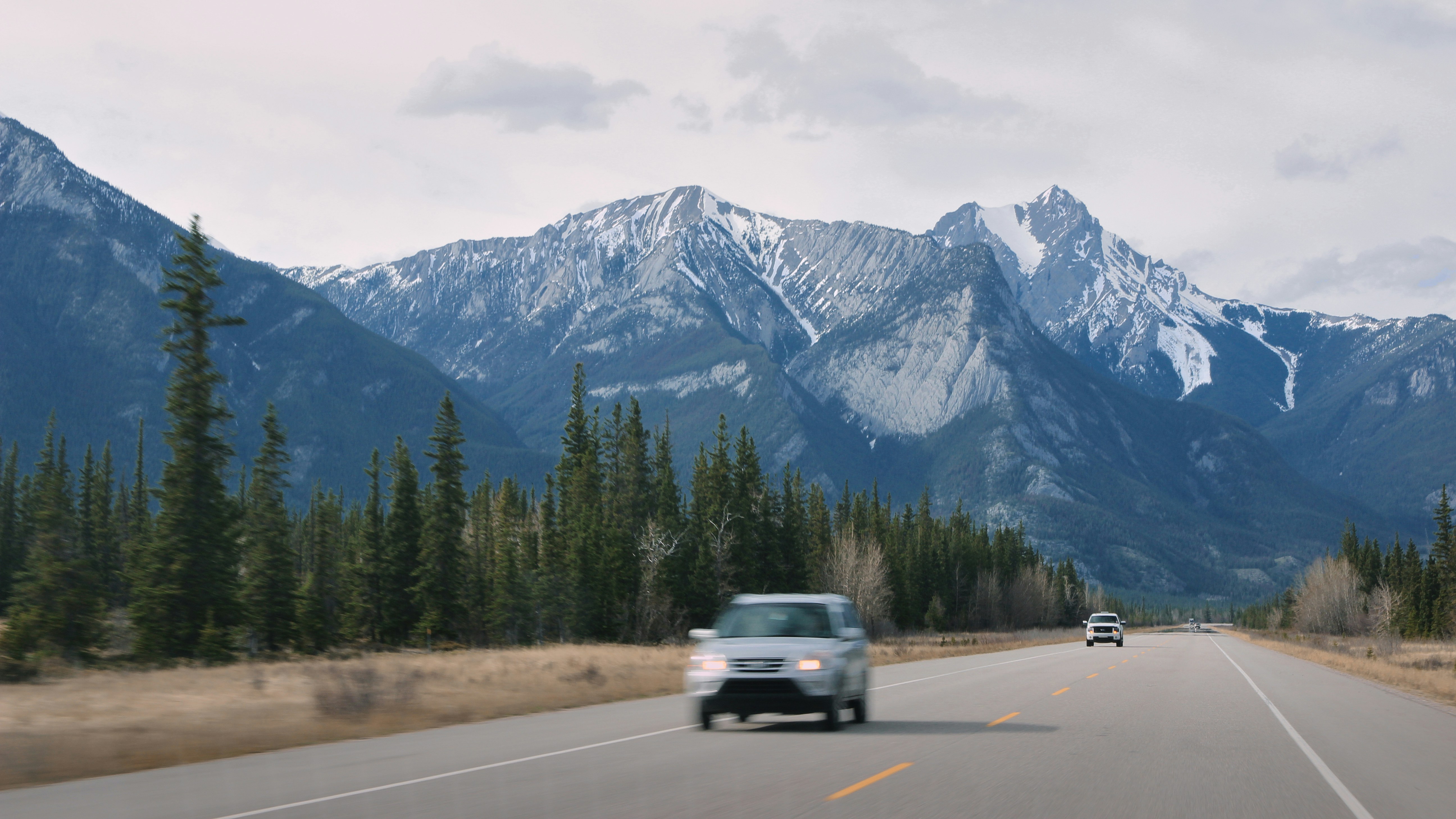 On the Mountain Pass: Cars Trace the Quiet Arc of a Snowy Horizon