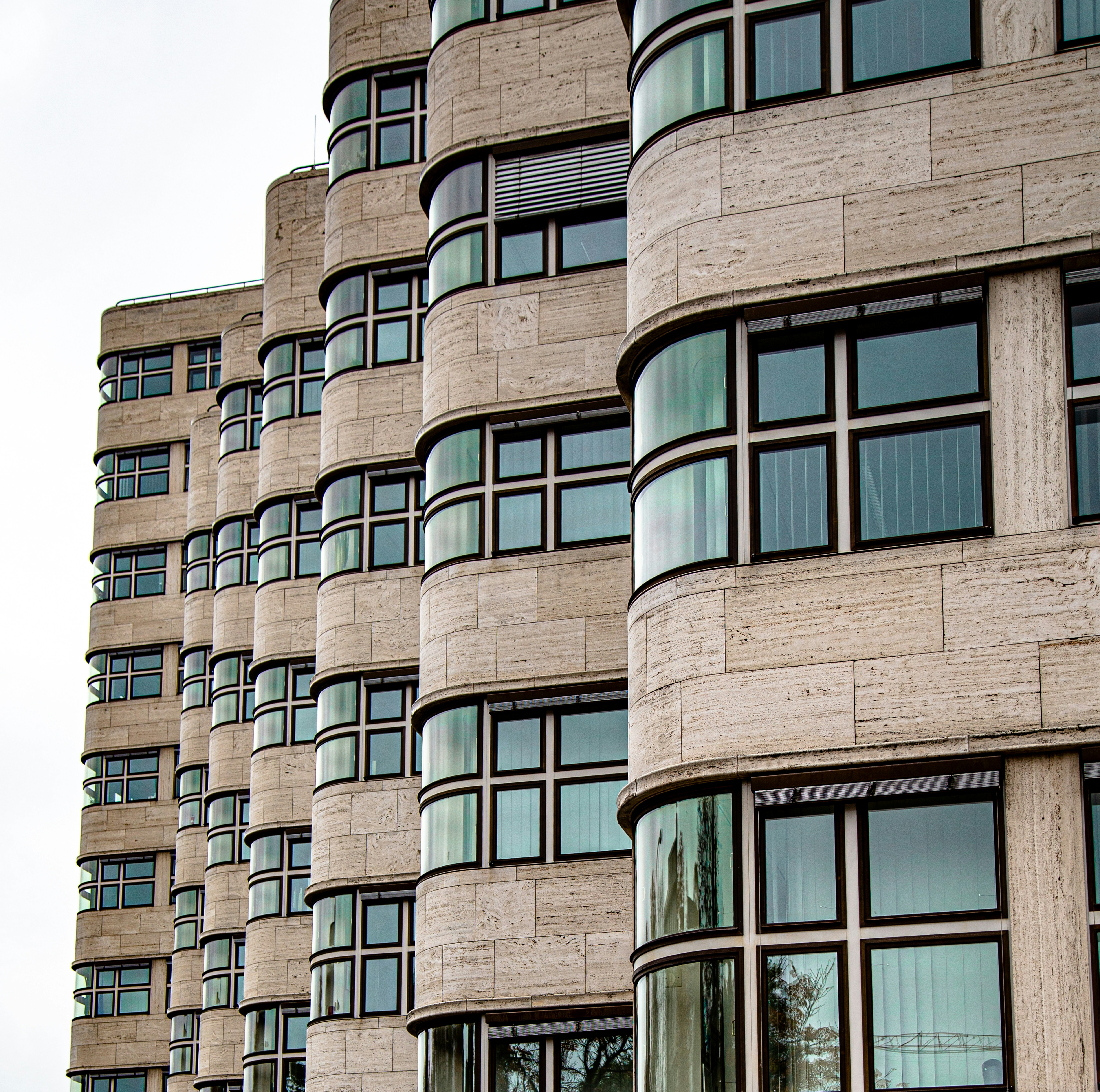 Unique building facade featuring a series of rounded windows and textured stone, showcasing contemporary design elements.