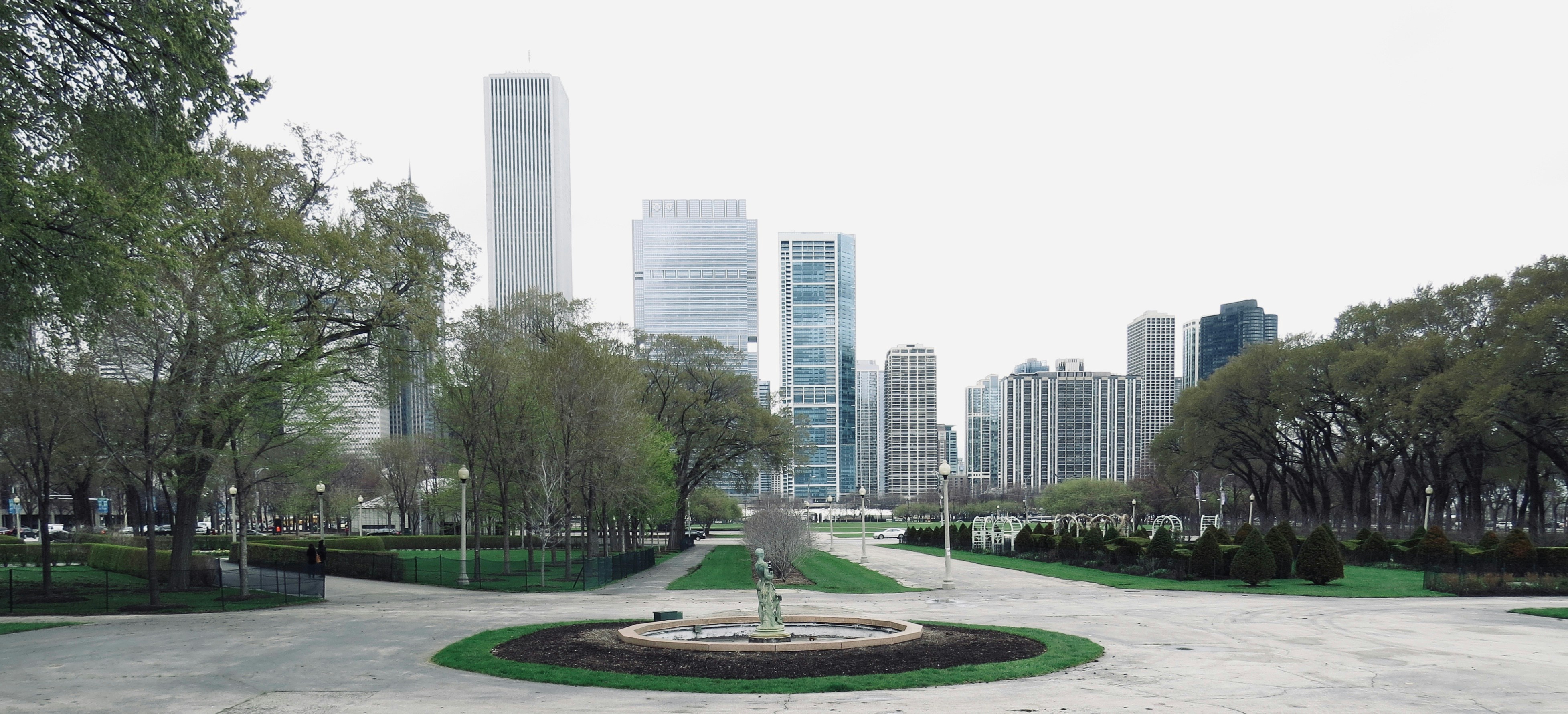 The Fountain’s Orbit: Park Pathways Converging on a Glassy Skyline