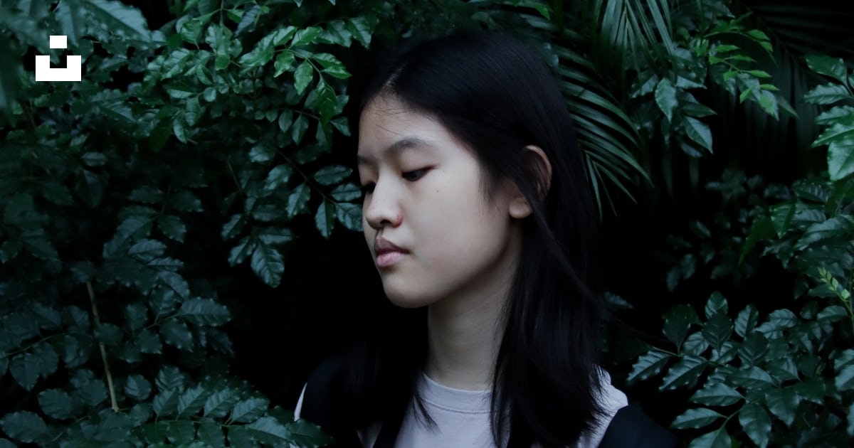 흰색과 검은색 긴팔 셔츠를 입은 여자가 녹색 잎 근처에 서 있다 사진 Unsplash의 무료 검정 이미지