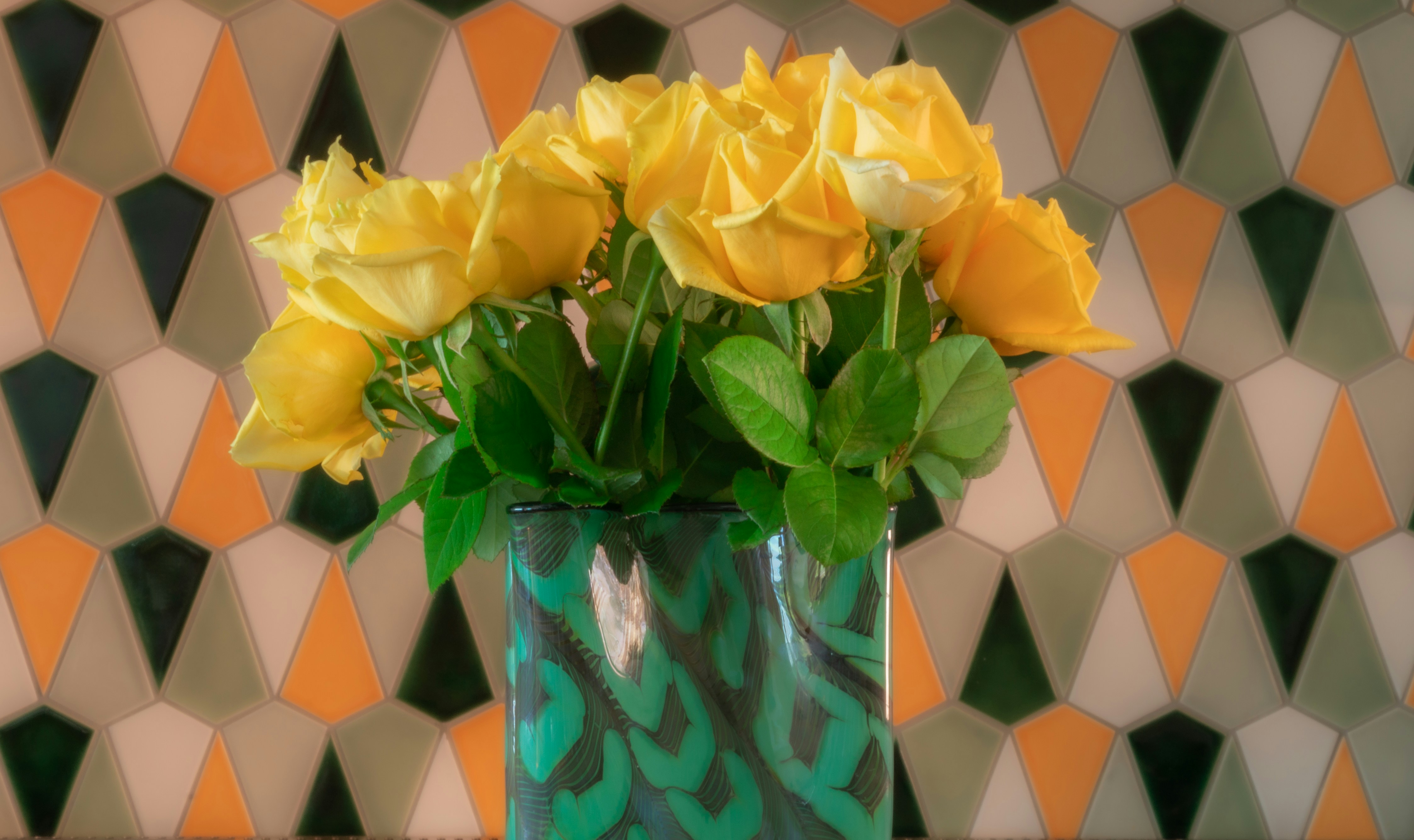 Geometric Backdrop Meets Golden Blooms in a Teal Vase