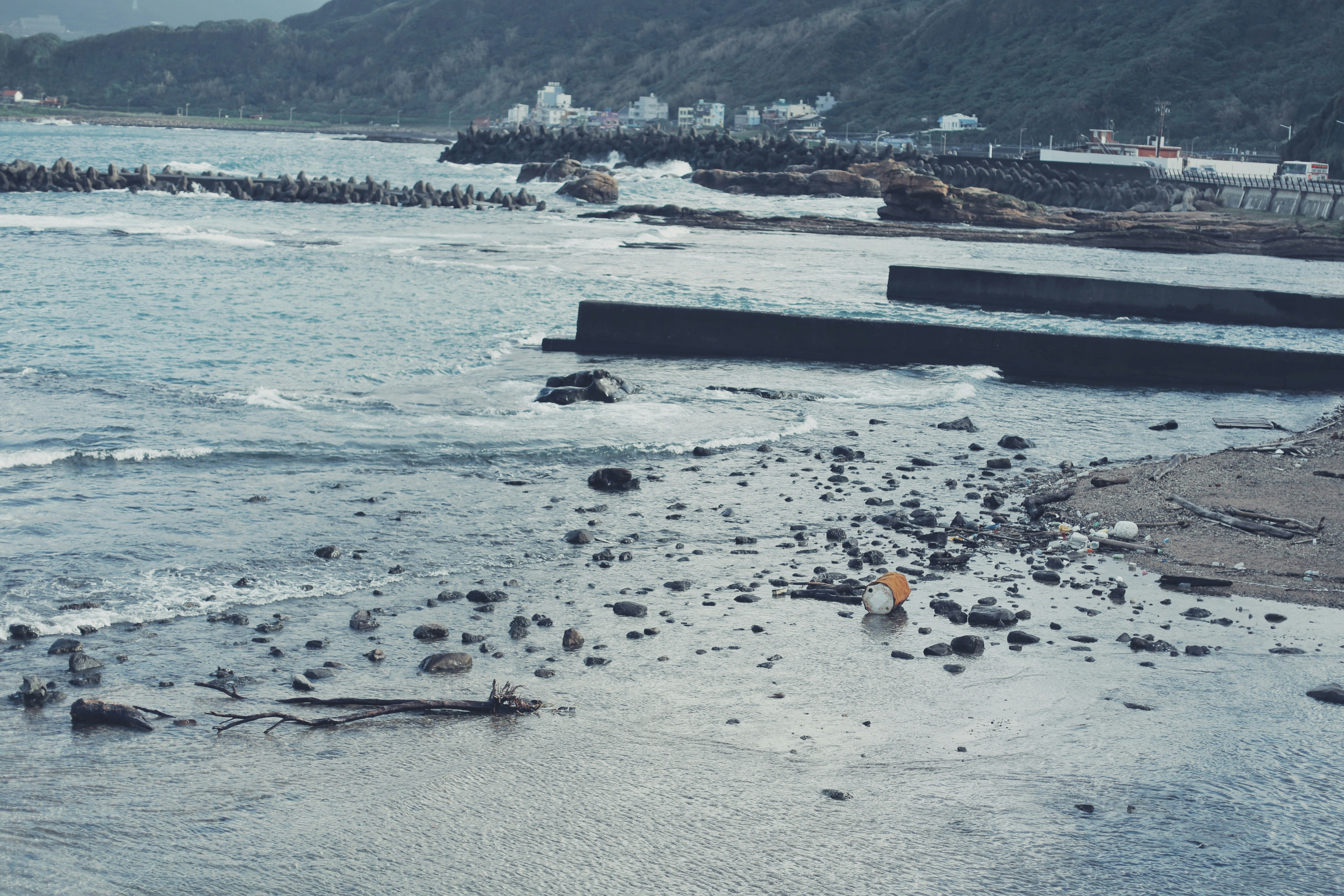 Amber Buoy Framed by Pebbles and Breakwaters on a Quiet Coastal Reach