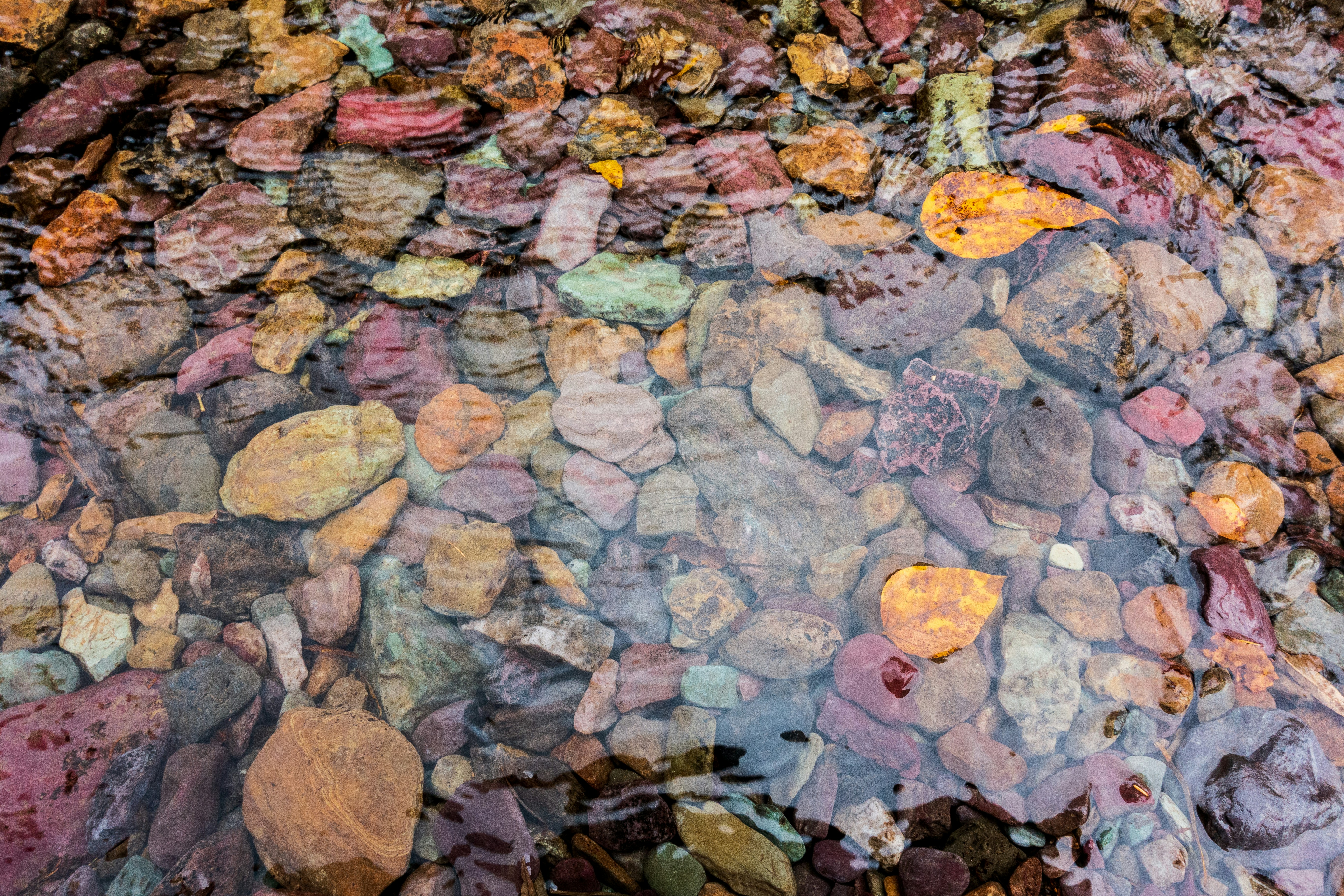 Colorful pebbles visible beneath the clear water surface, showcasing a natural mosaic.