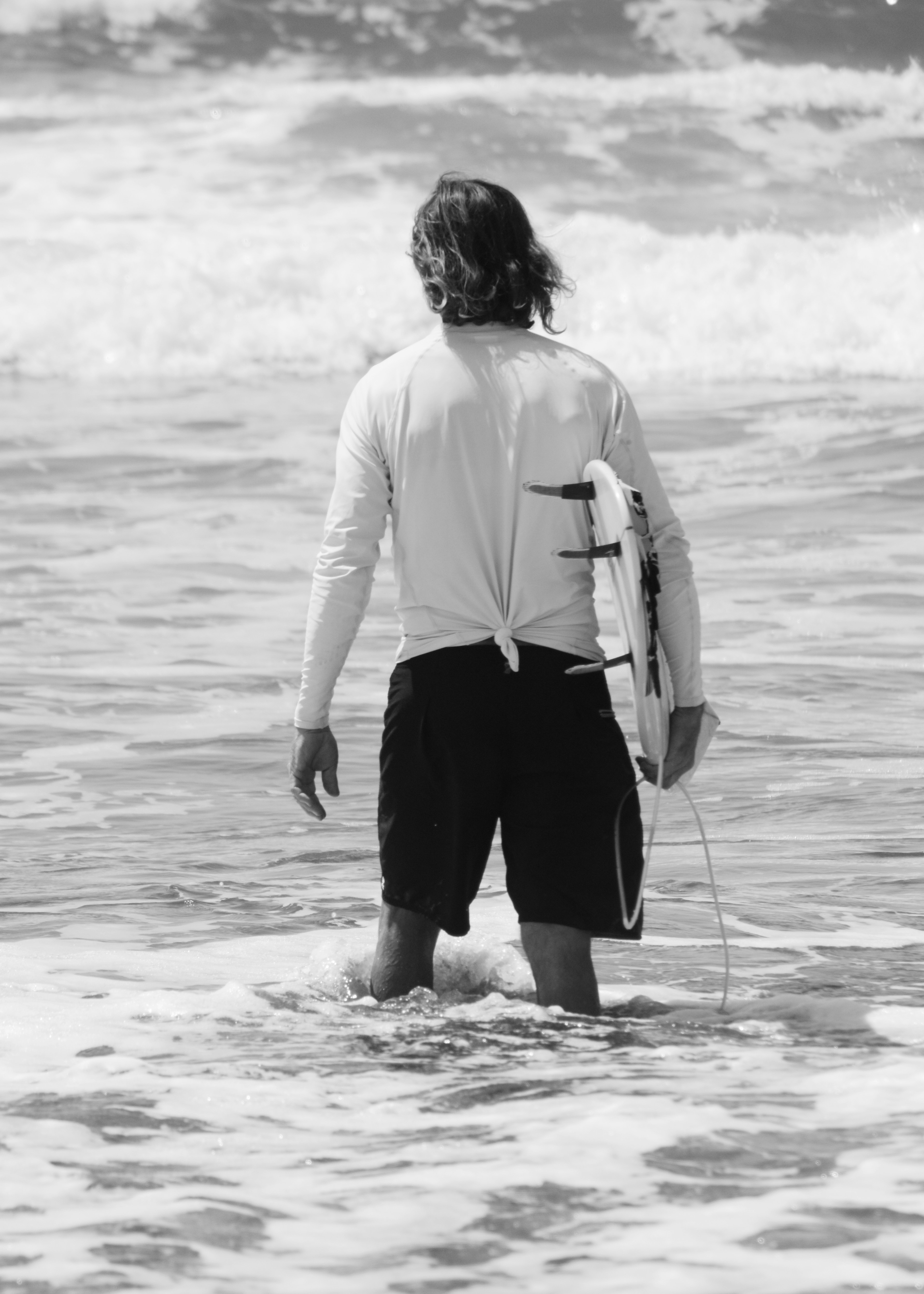 Back-View Surfer at the Shore: Board in Hand, Quiet Tide